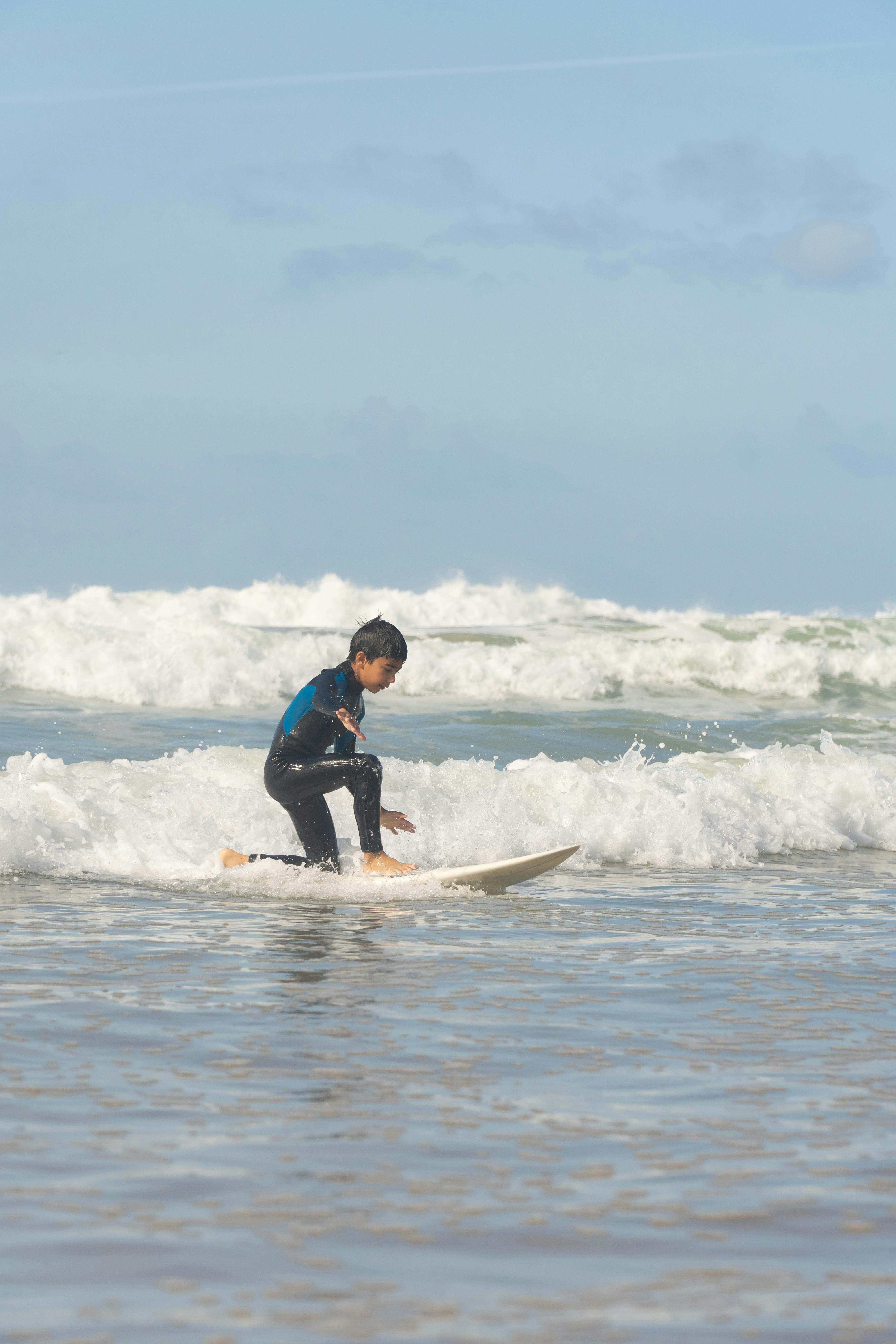 A Boy Balancing on a Surfboard on Sea Waves · Free Stock Photo