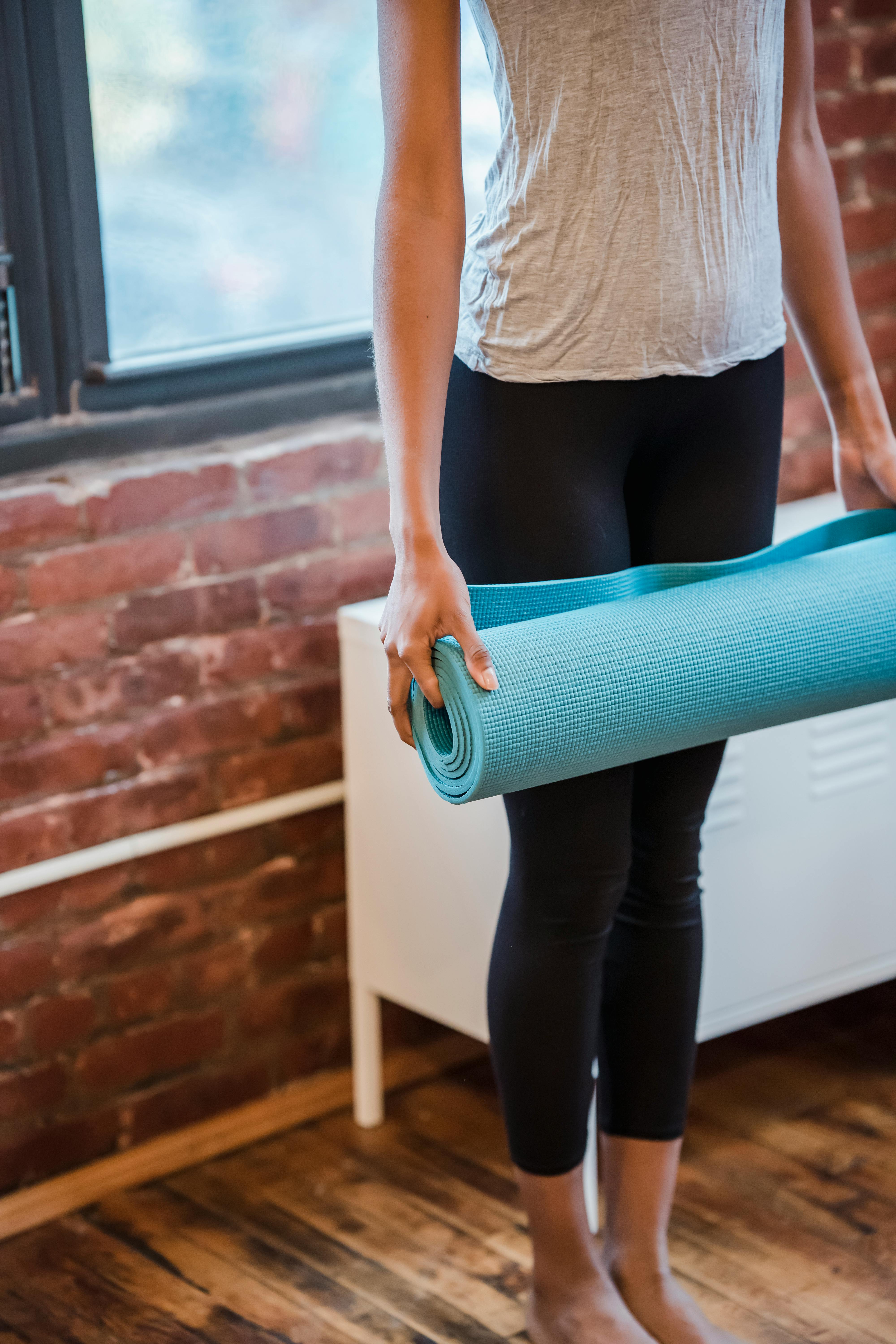 Person standing with yoga mat in studio · Free Stock Photo