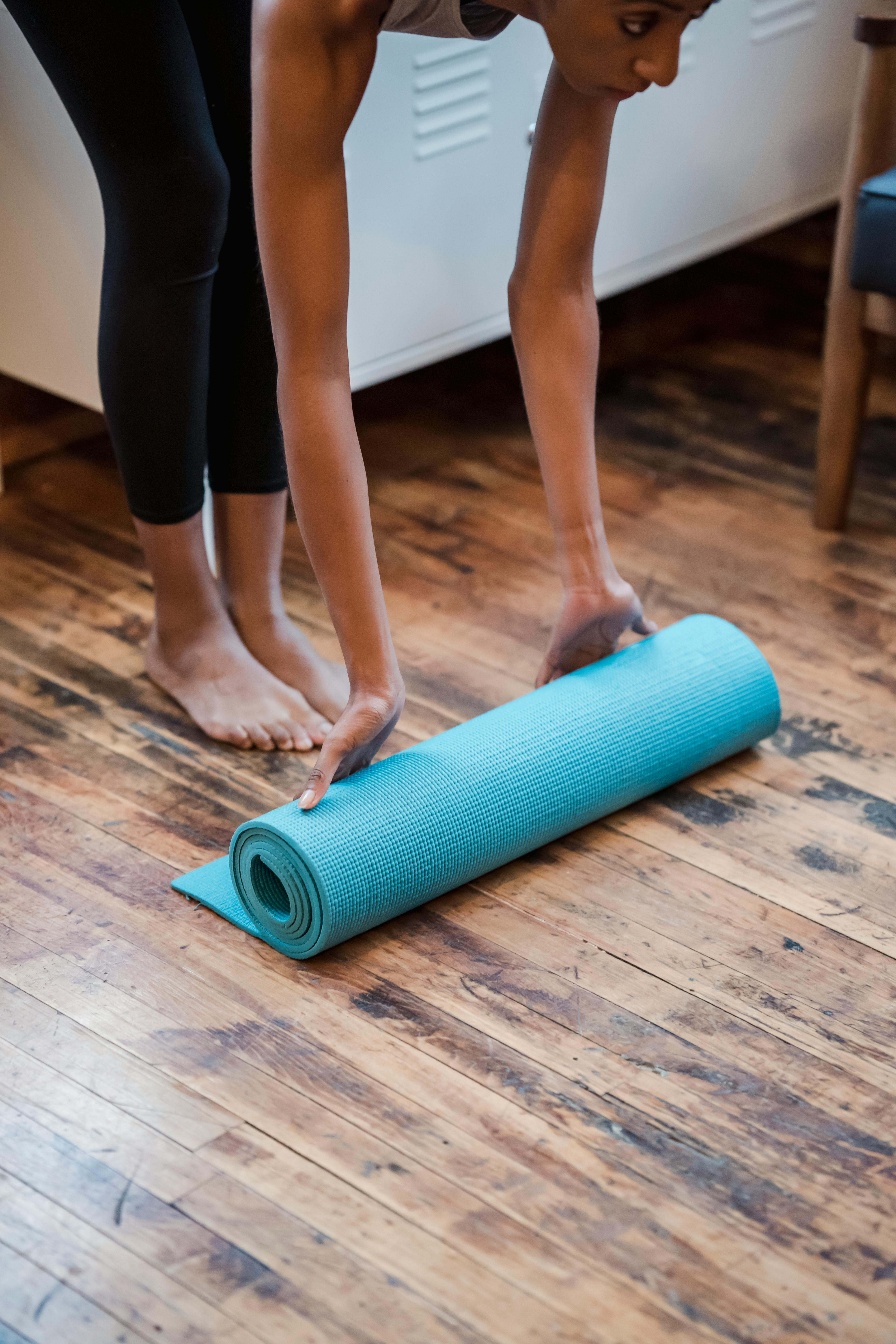 Black female placing yoga mat on floor in room · Free Stock Photo