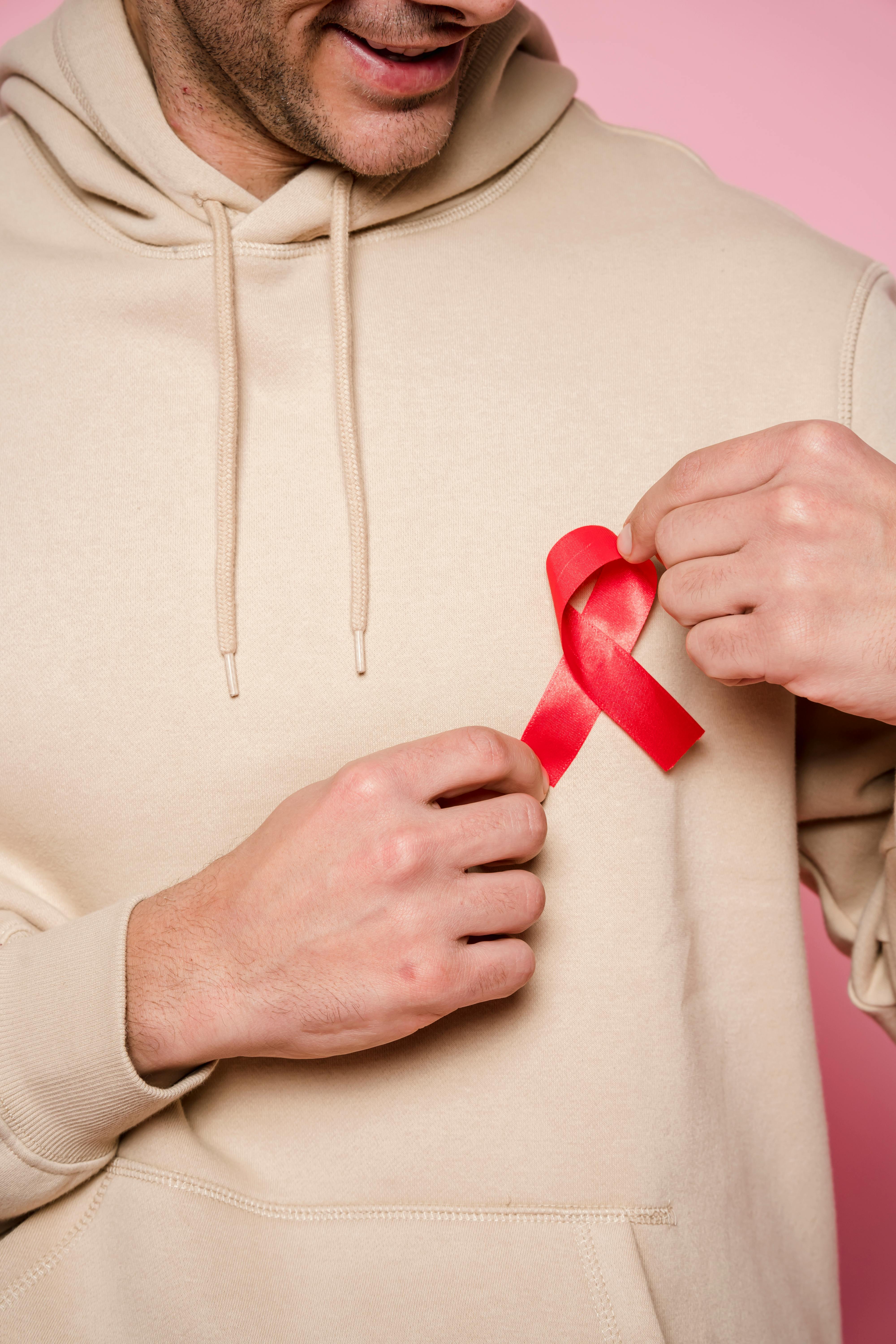 Person Putting A Red Ribbon On His Clothing · Free Stock Photo
