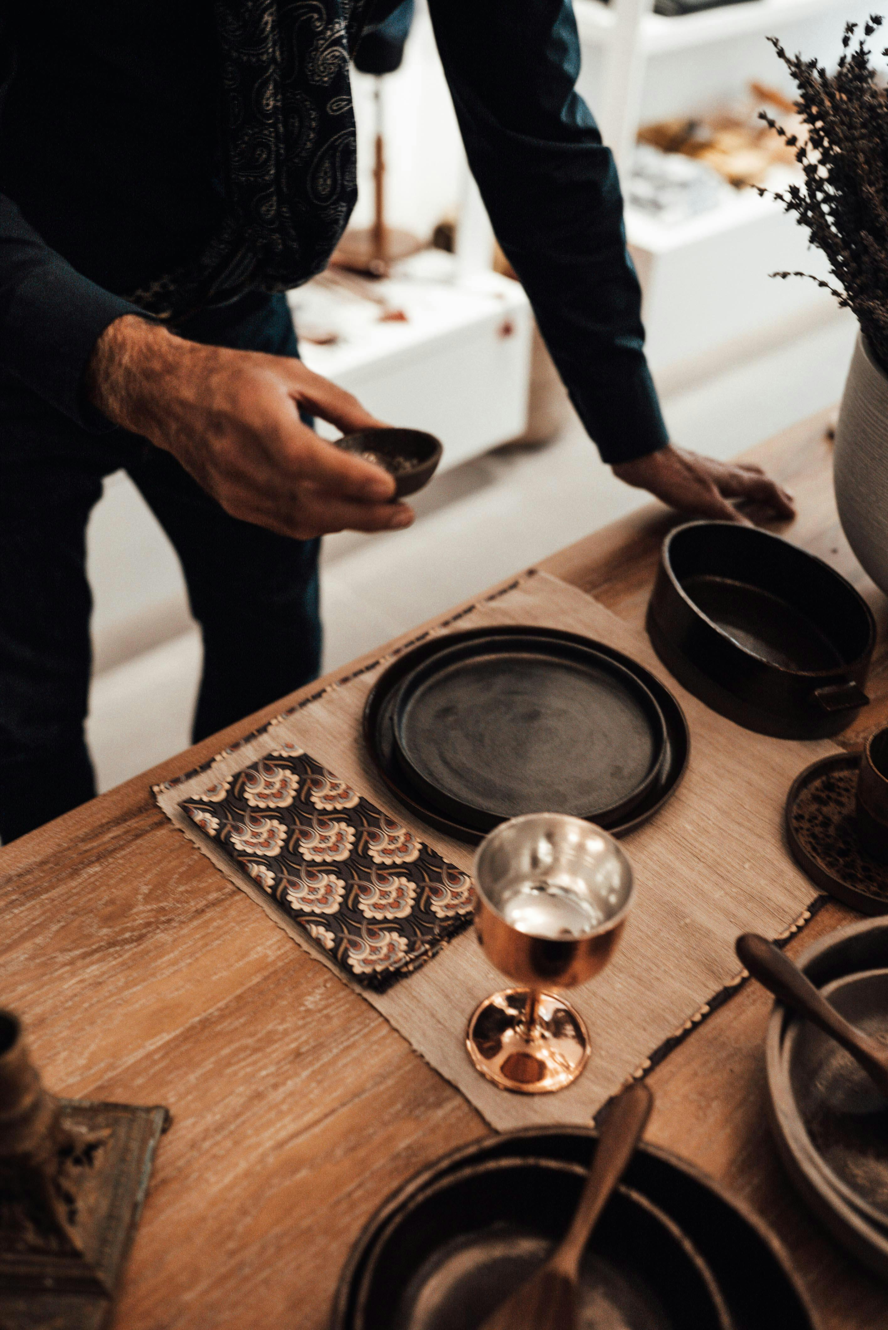 Crop ethnic vendor at table with antique dishware · Free Stock Photo