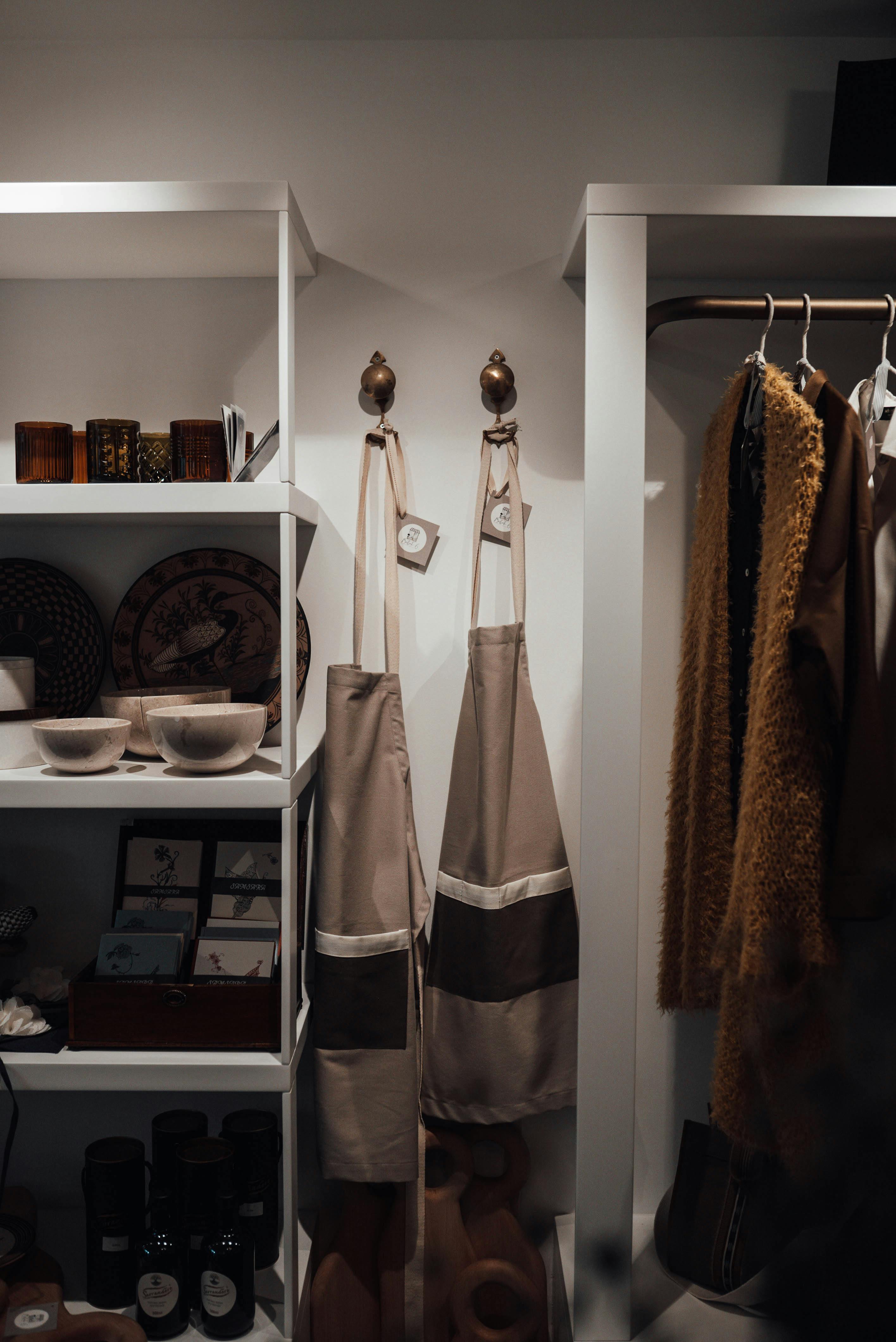 Collection of trendy clothes and assorted pottery in modern boutique ...