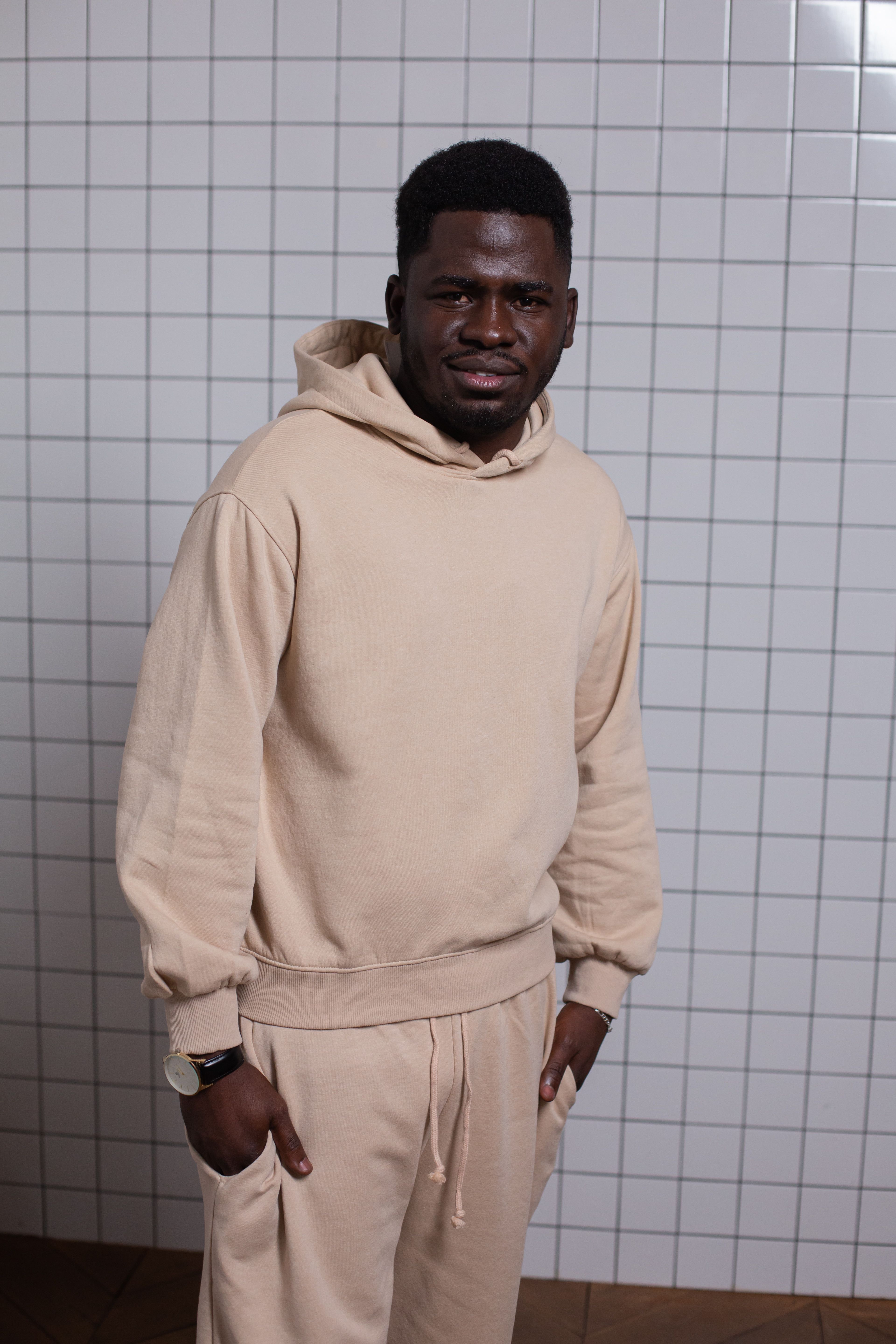 Stylish African American man in black hoodie standing near rough wall ...