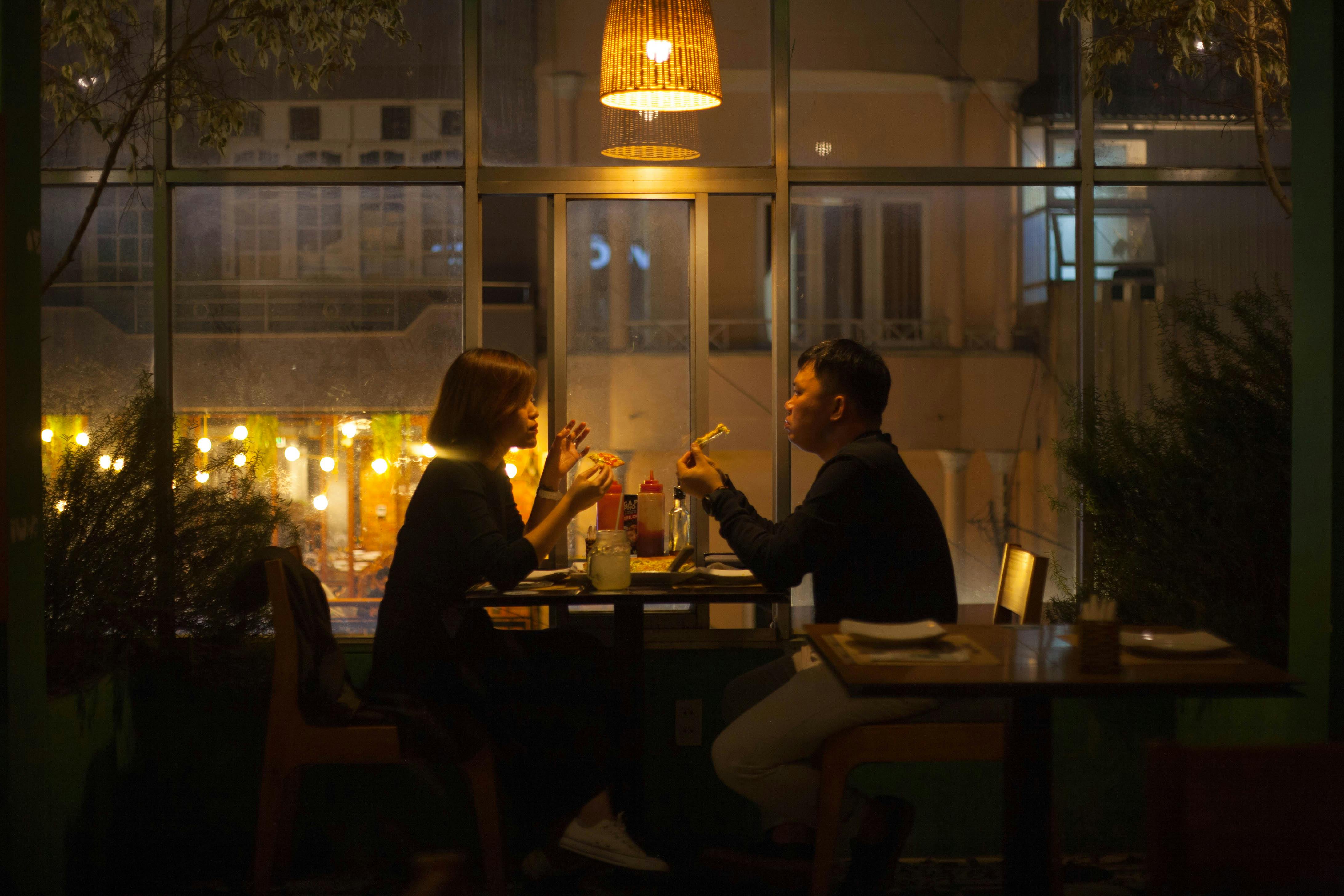 A Man and a Woman Eating by the Window of a Restaurant · Free Stock Photo