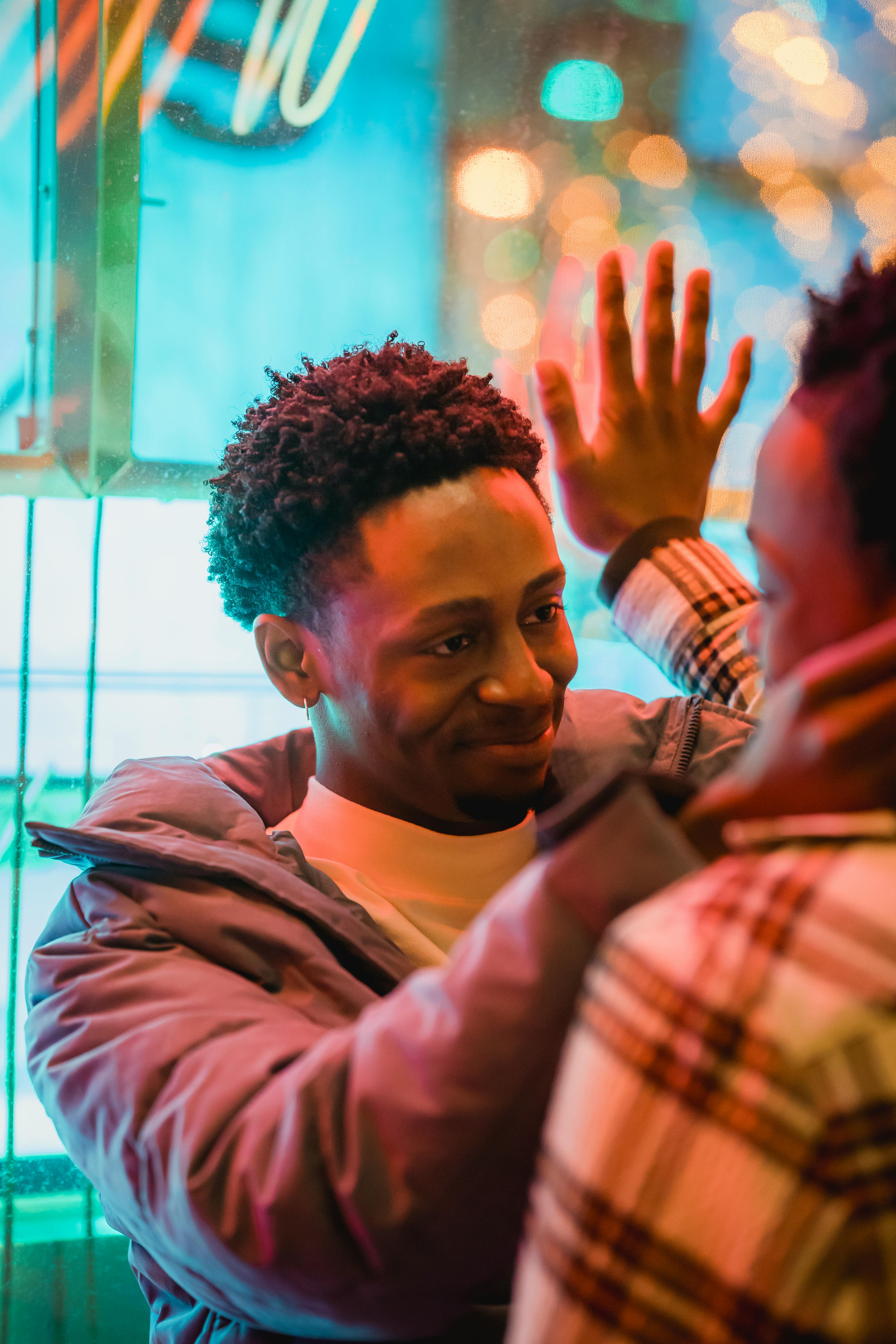 Cheerful black men touching each other near glass wall · Free Stock Photo