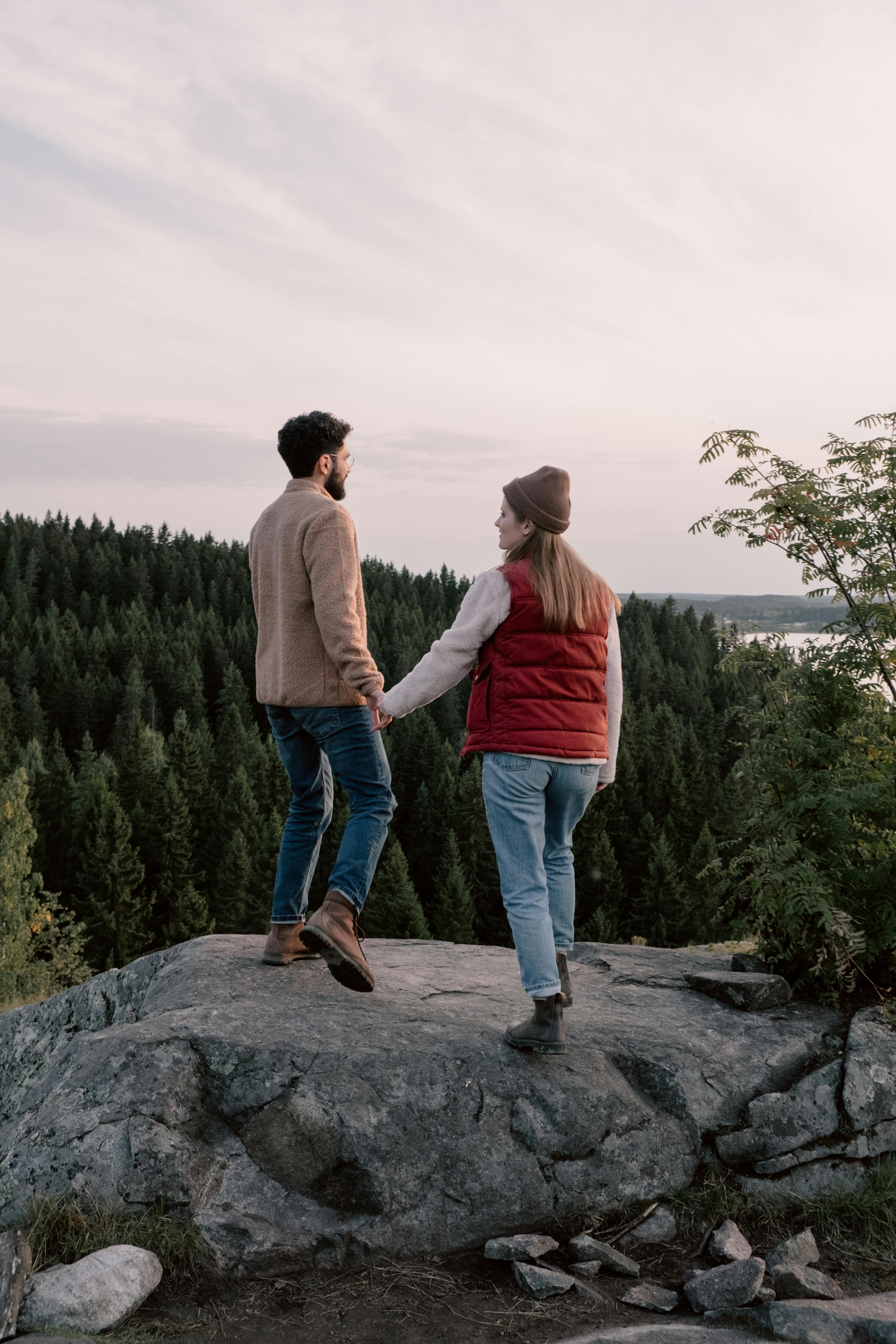 A Couple Holding Hands While Walking on a Rock · Free Stock Photo