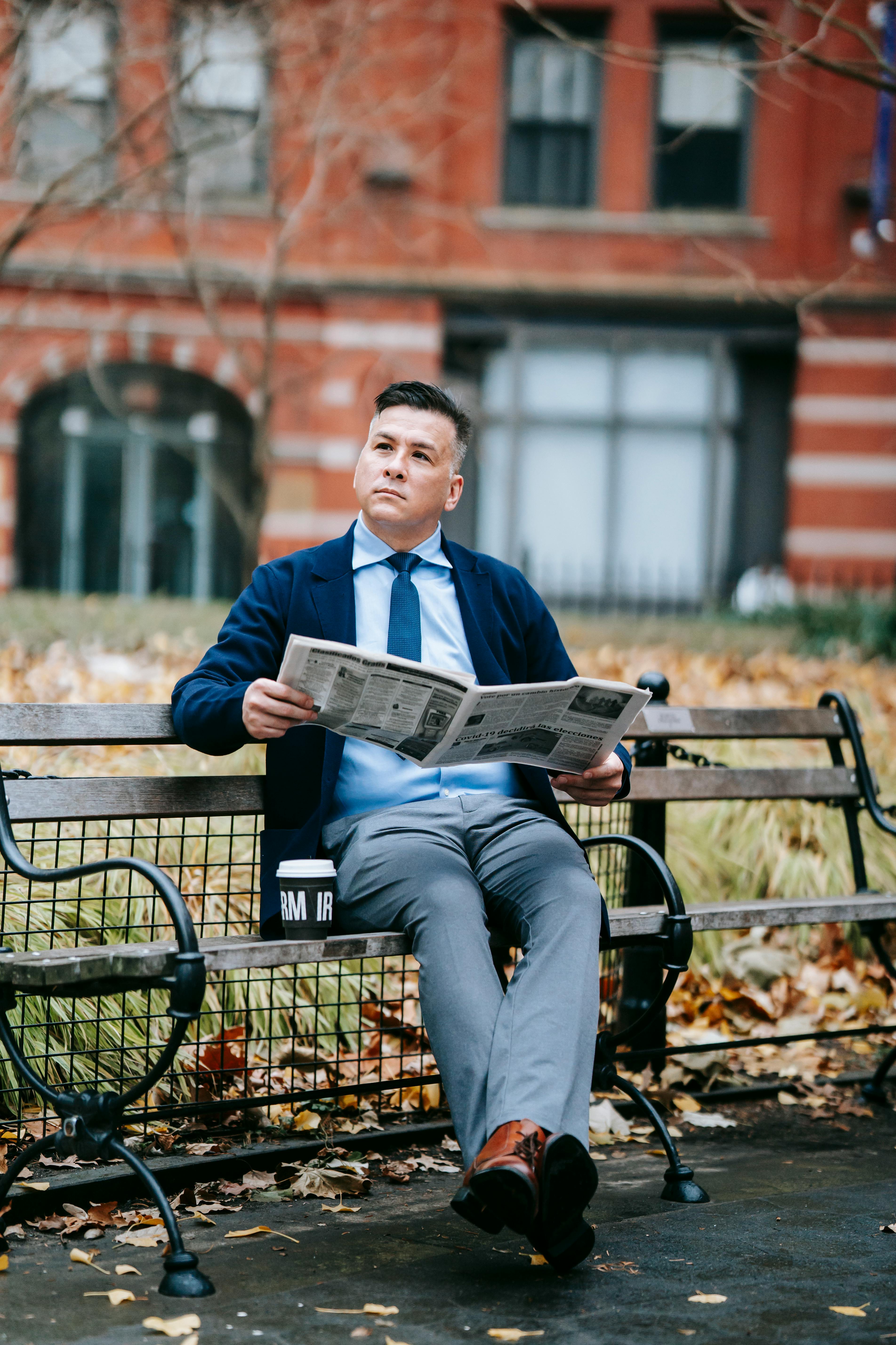 Photo Of Man Holding Newspaper While Sitting On A Wooden Bench · Free ...