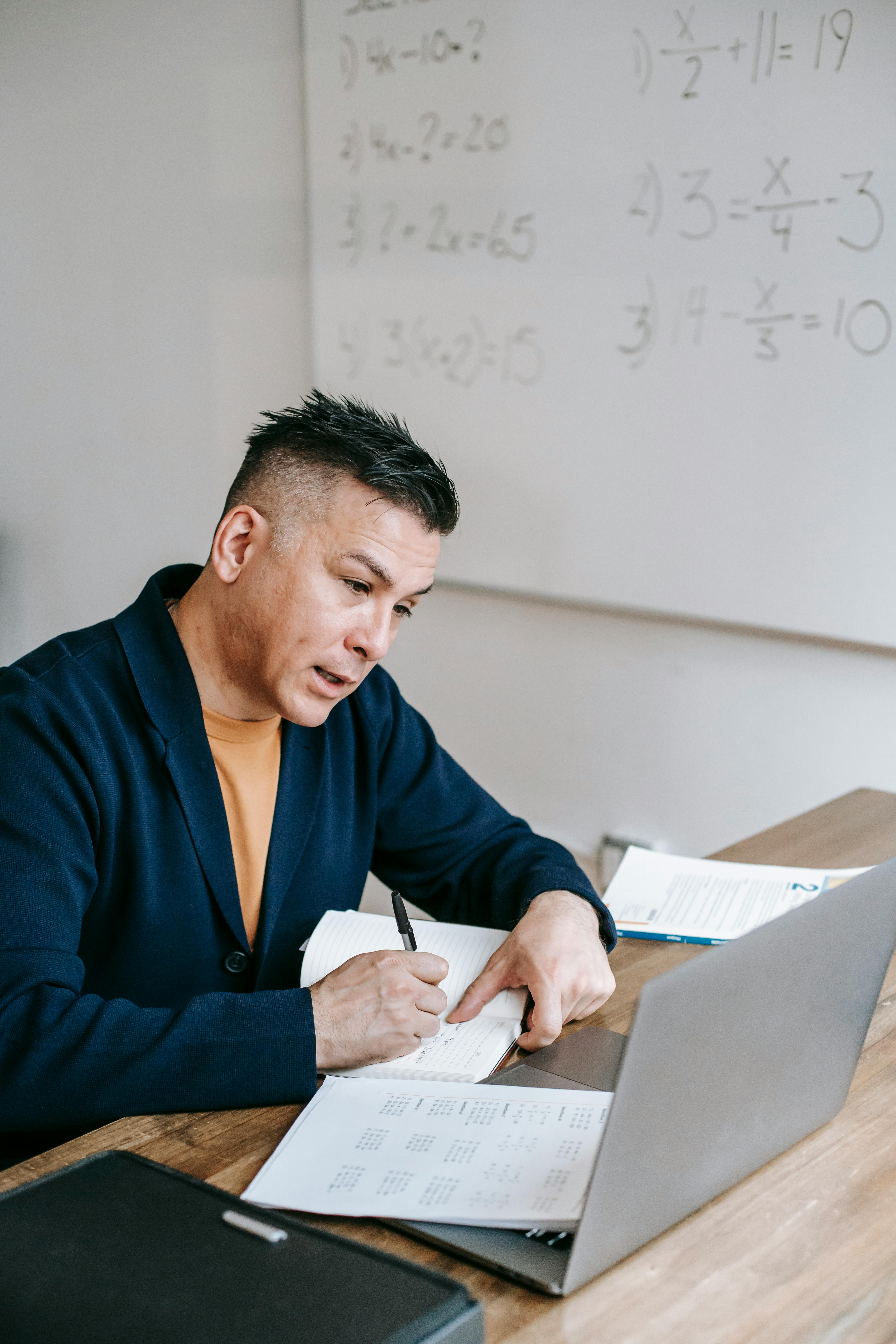 Photo Of Man Writing While Looking On The Laptop · Free Stock Photo