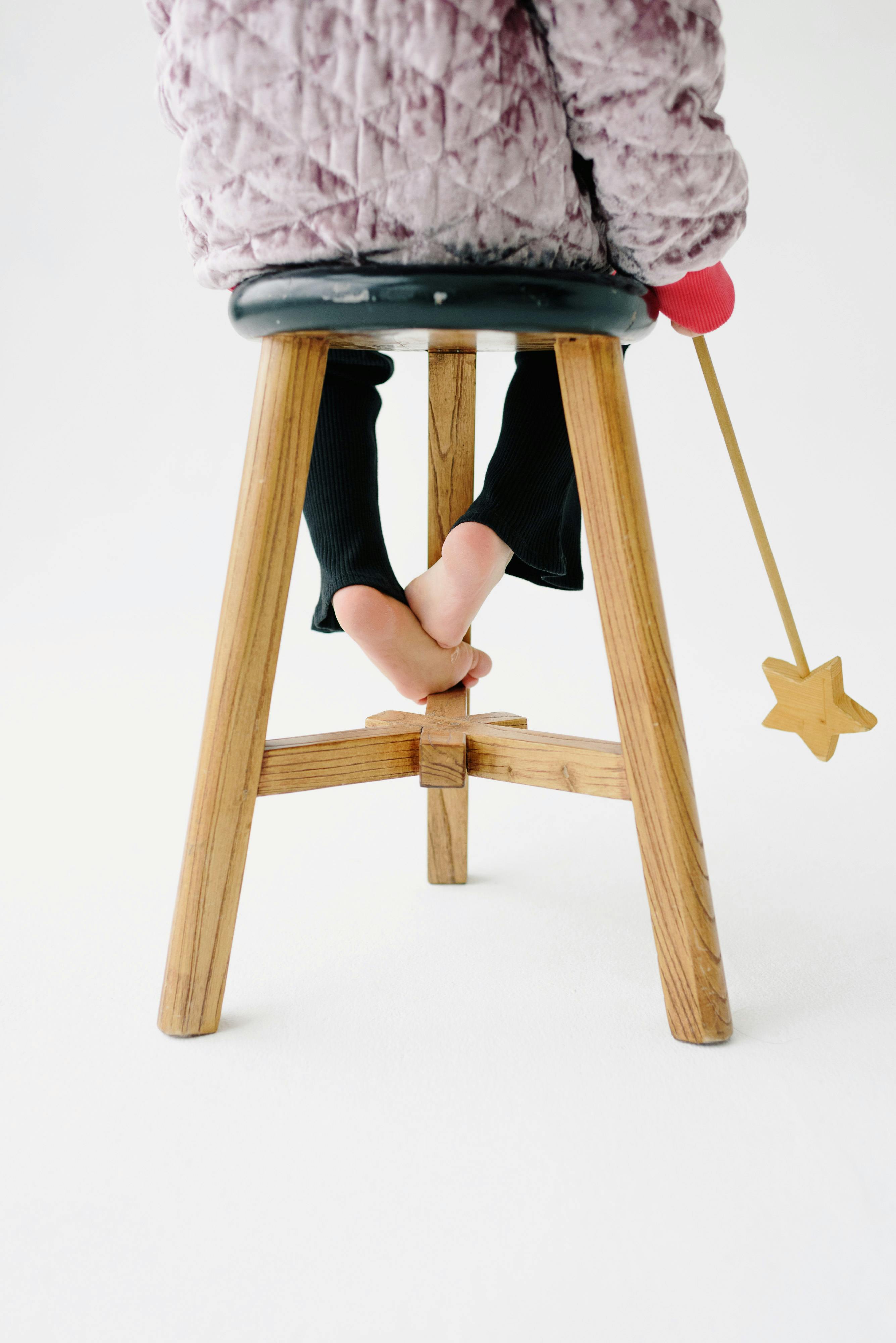 Back View of a Child with Bare Feet and a Magic Wand Sitting on a Stool ...