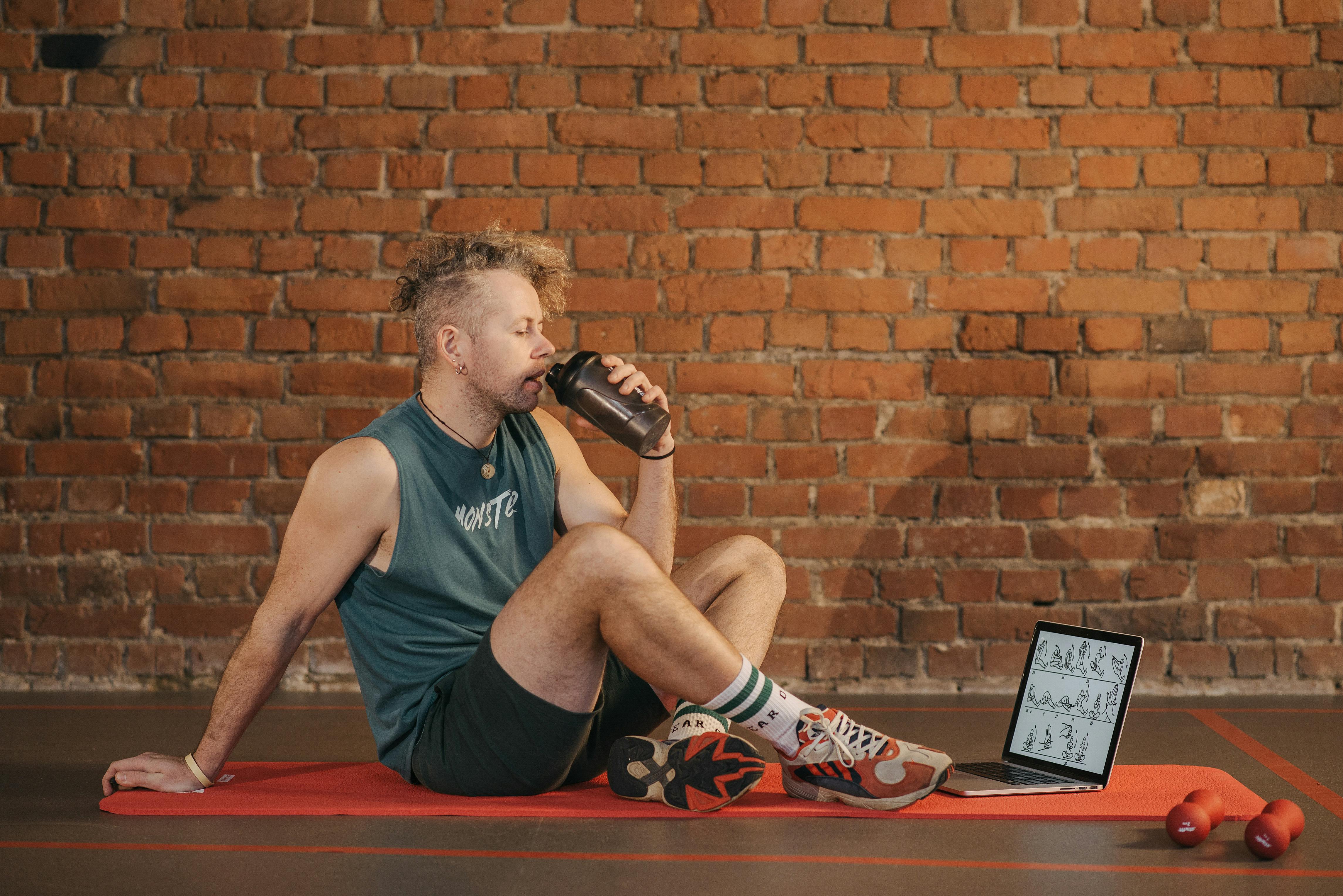 Man Sitting on Exercise Mat While Drinking from a Tumbler · Free Stock ...