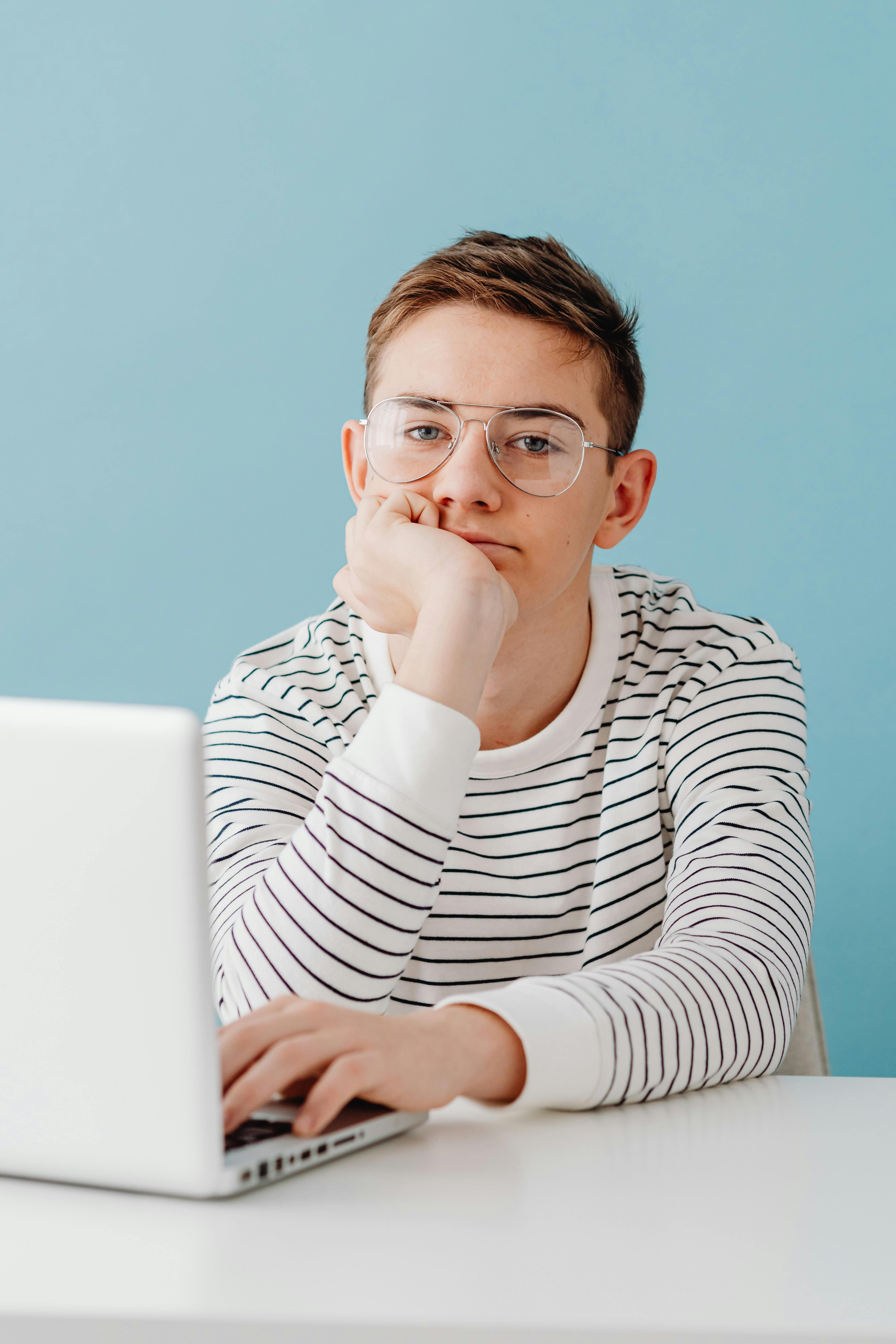 Teenage Boy with Eyeglasses and a Laptop on a Desk · Free Stock Photo