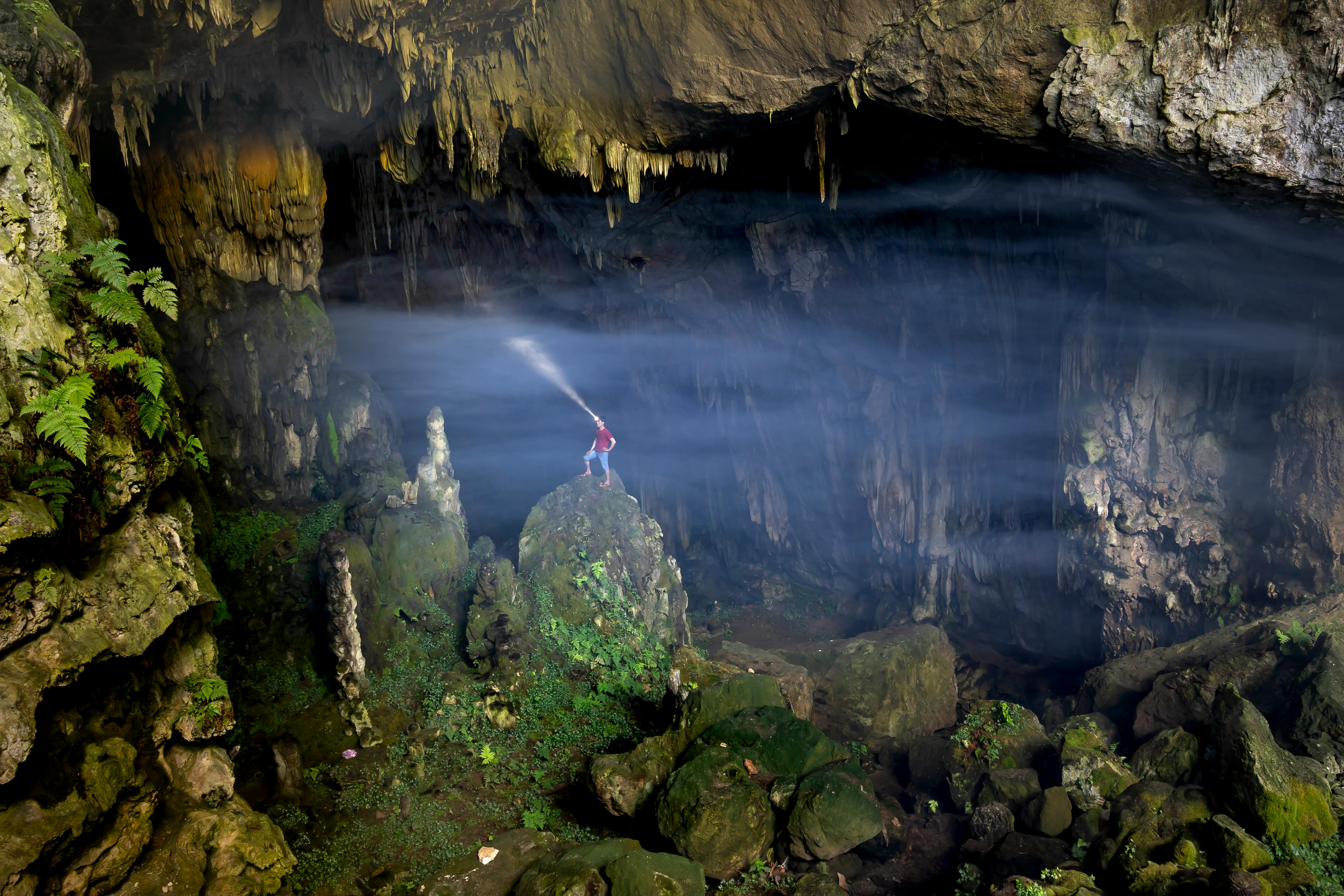 A Man Standing on the Big Rock in a Cave · Free Stock Photo