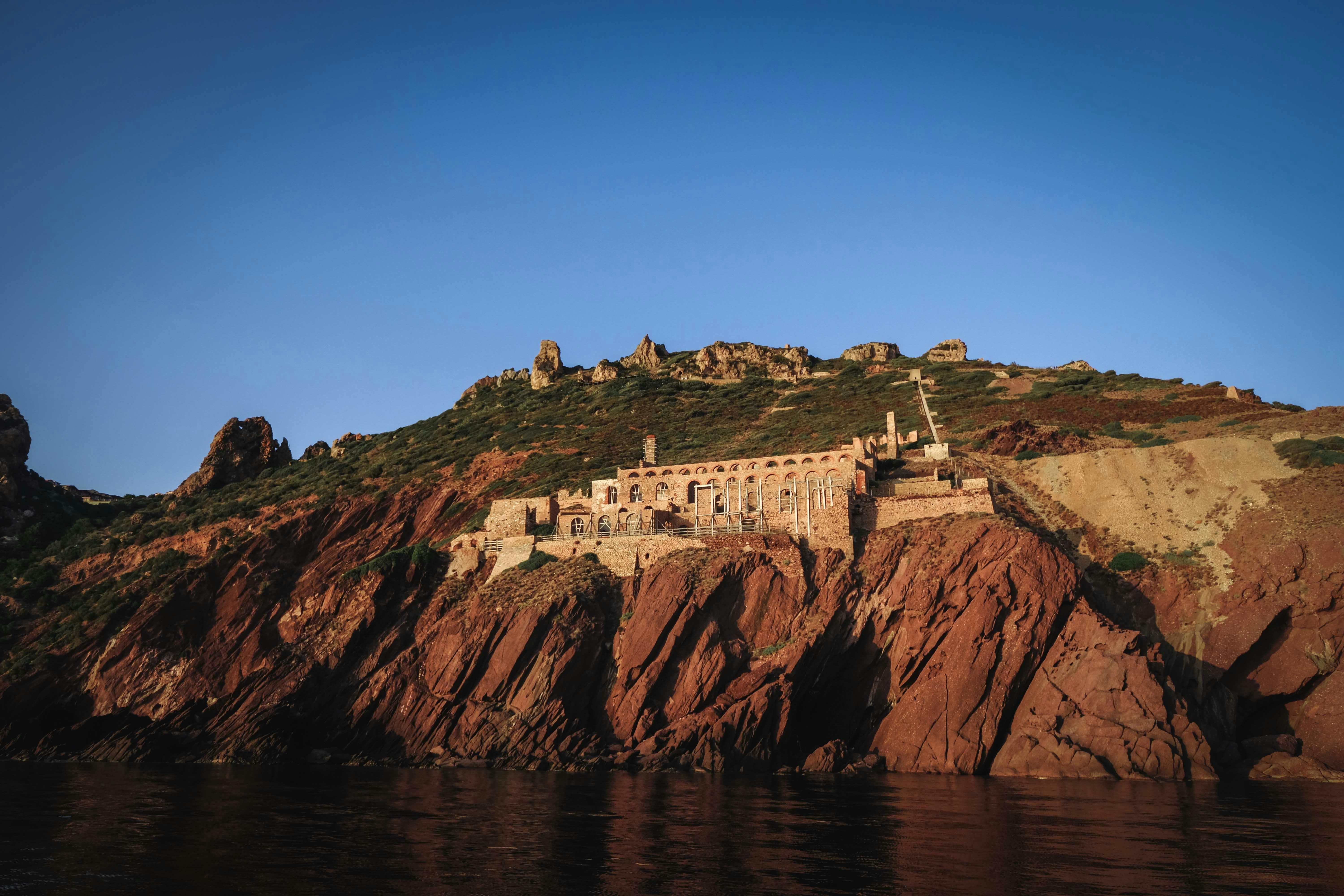 Old mining complex built on rocky cliff above sea in Sardinia · Free ...