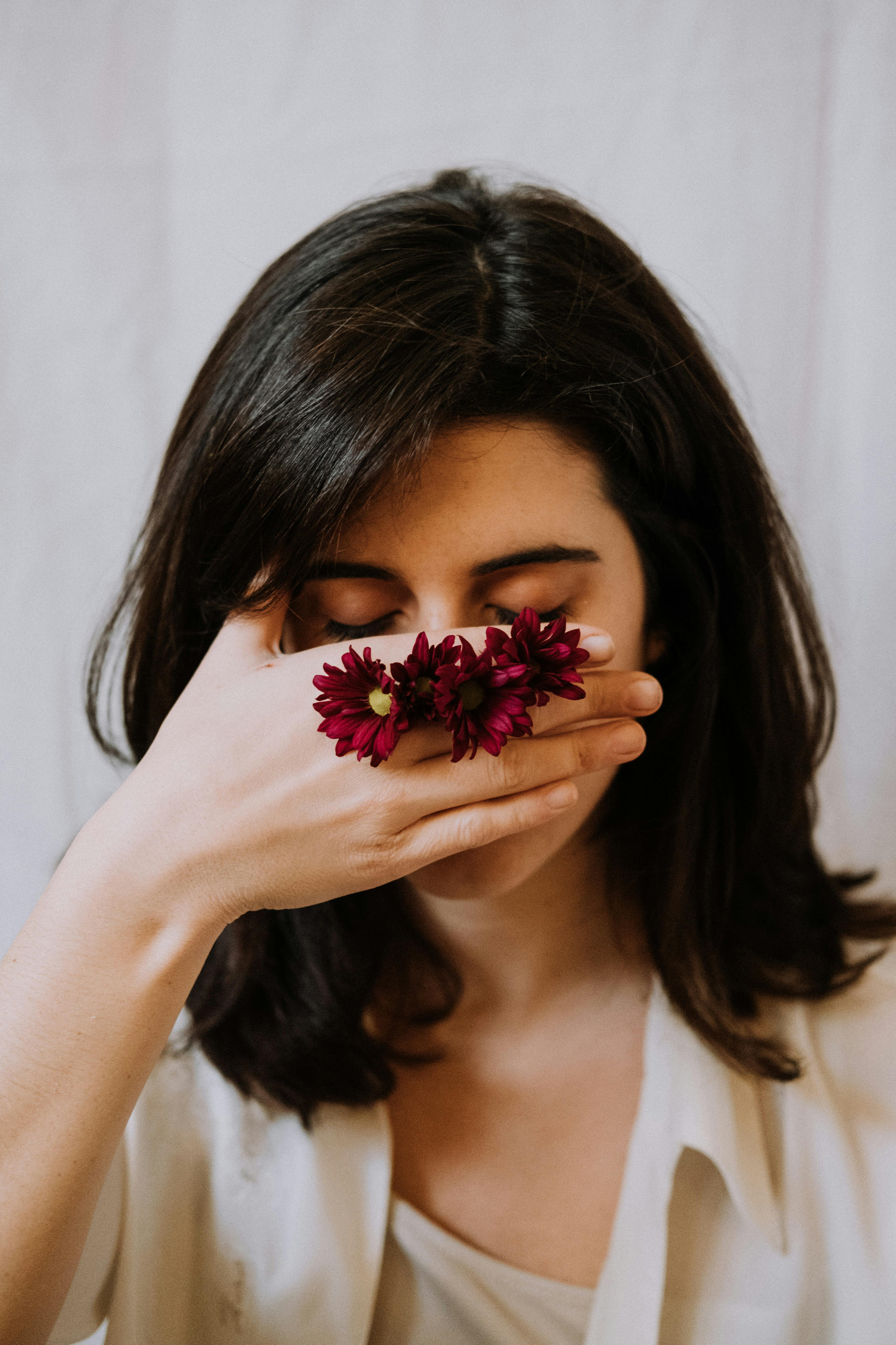 Serene female covering face with blooming flowers · Free Stock Photo