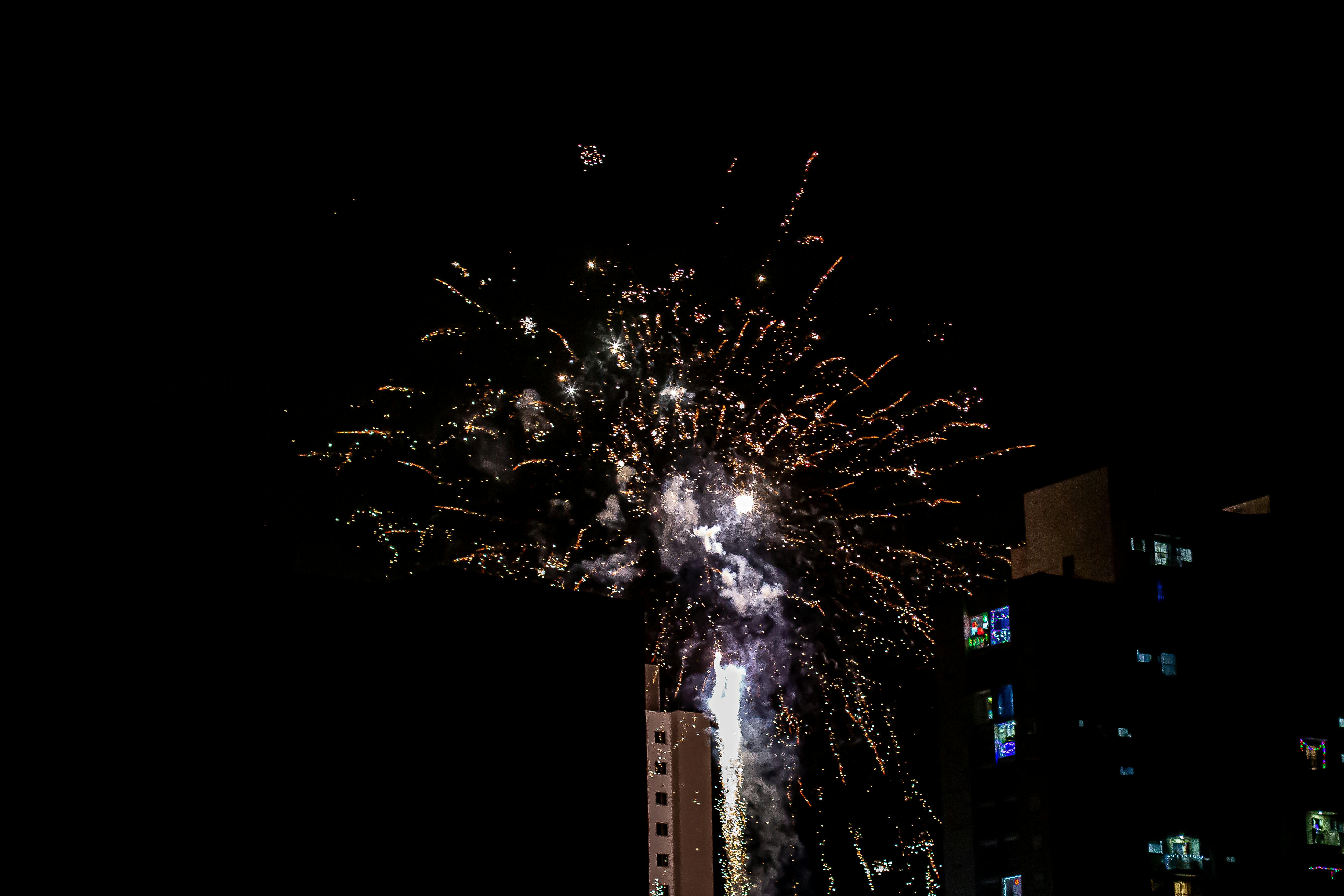 Glowing firework exploding above tall building · Free Stock Photo