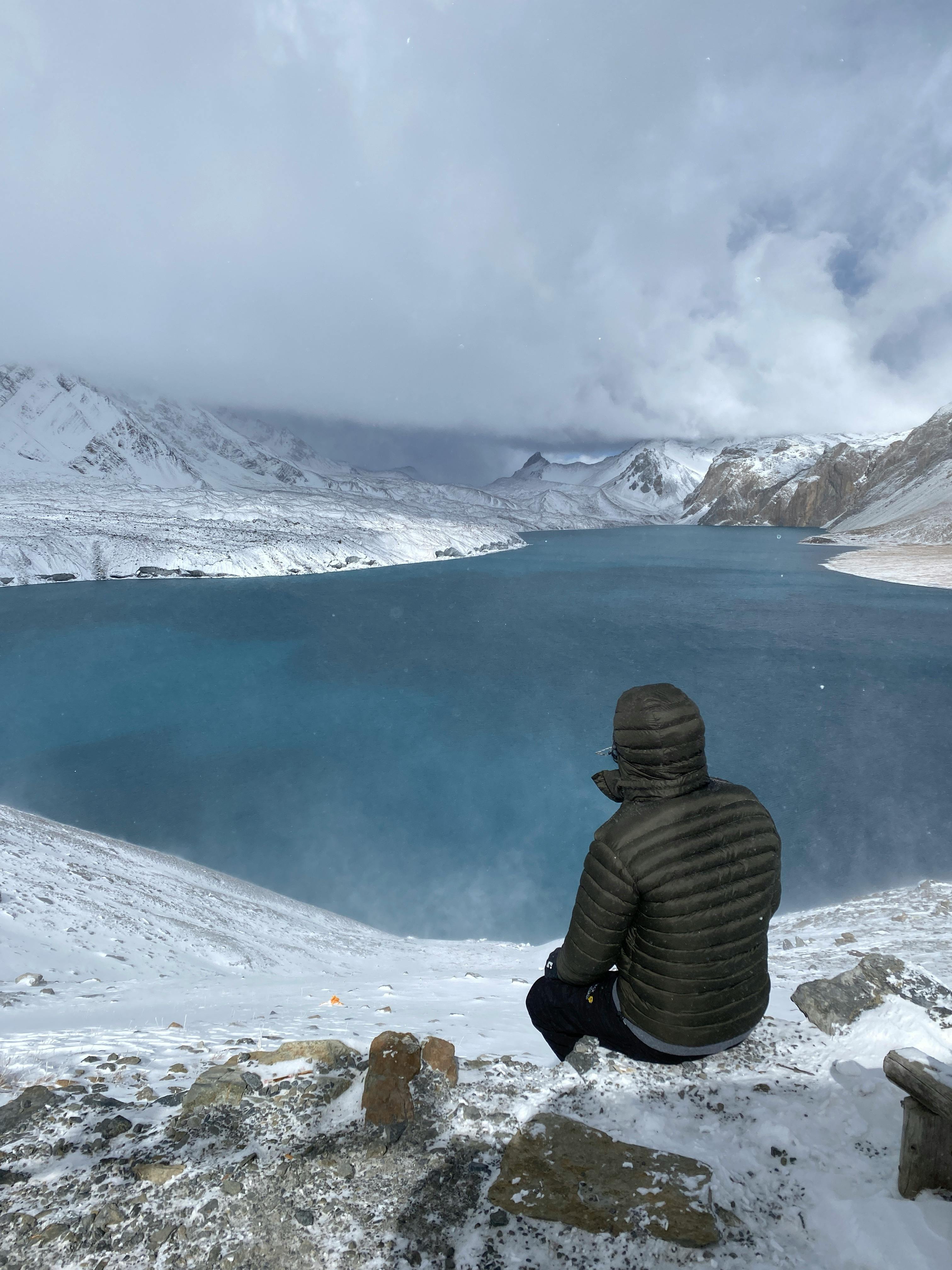 Back View of a Man Sitting Near a Frozen Lake · Free Stock Photo