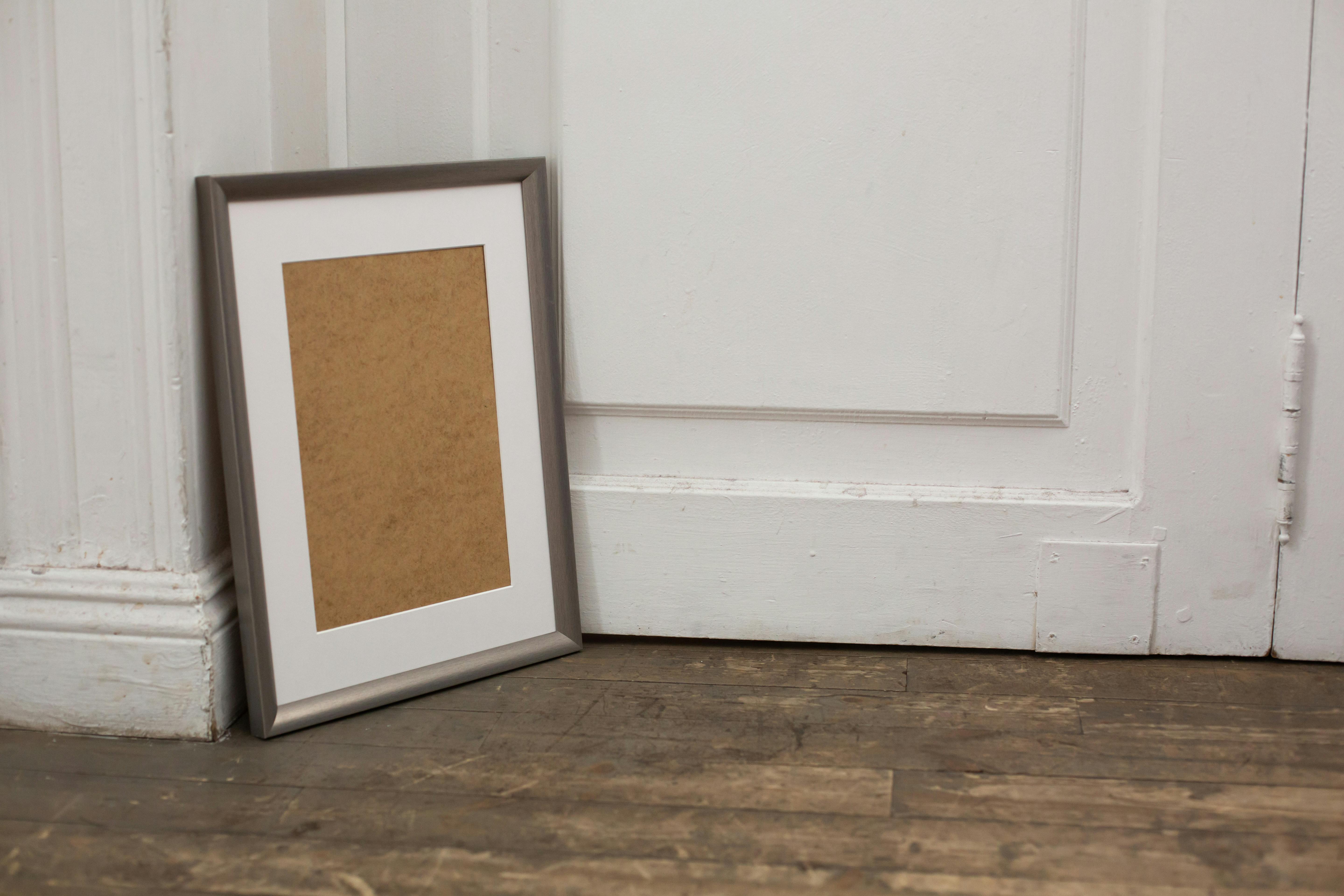 Modern simple frame hanging on wall between windows · Free Stock Photo