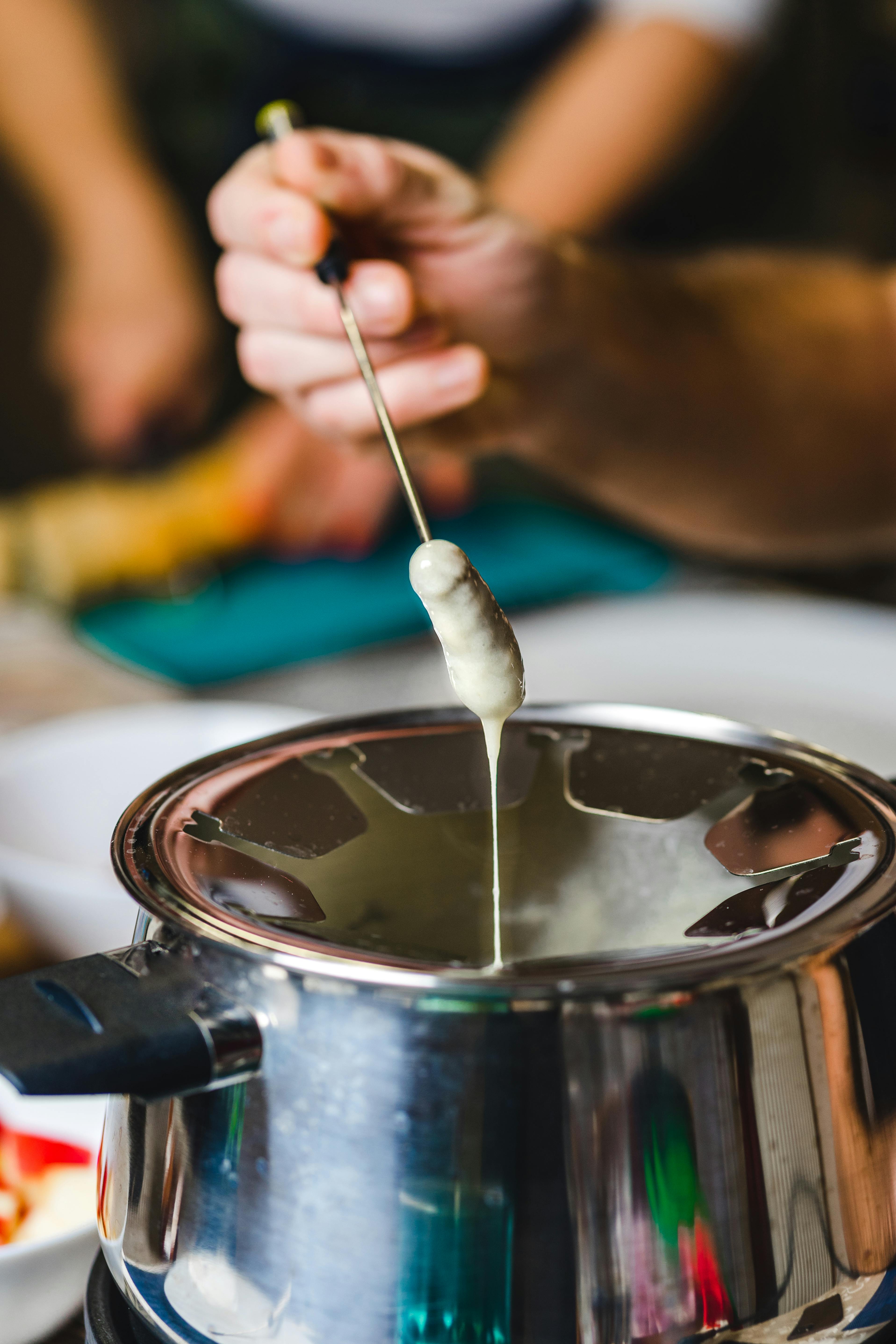 A Person Dipping Food in Melted Cheese · Free Stock Photo