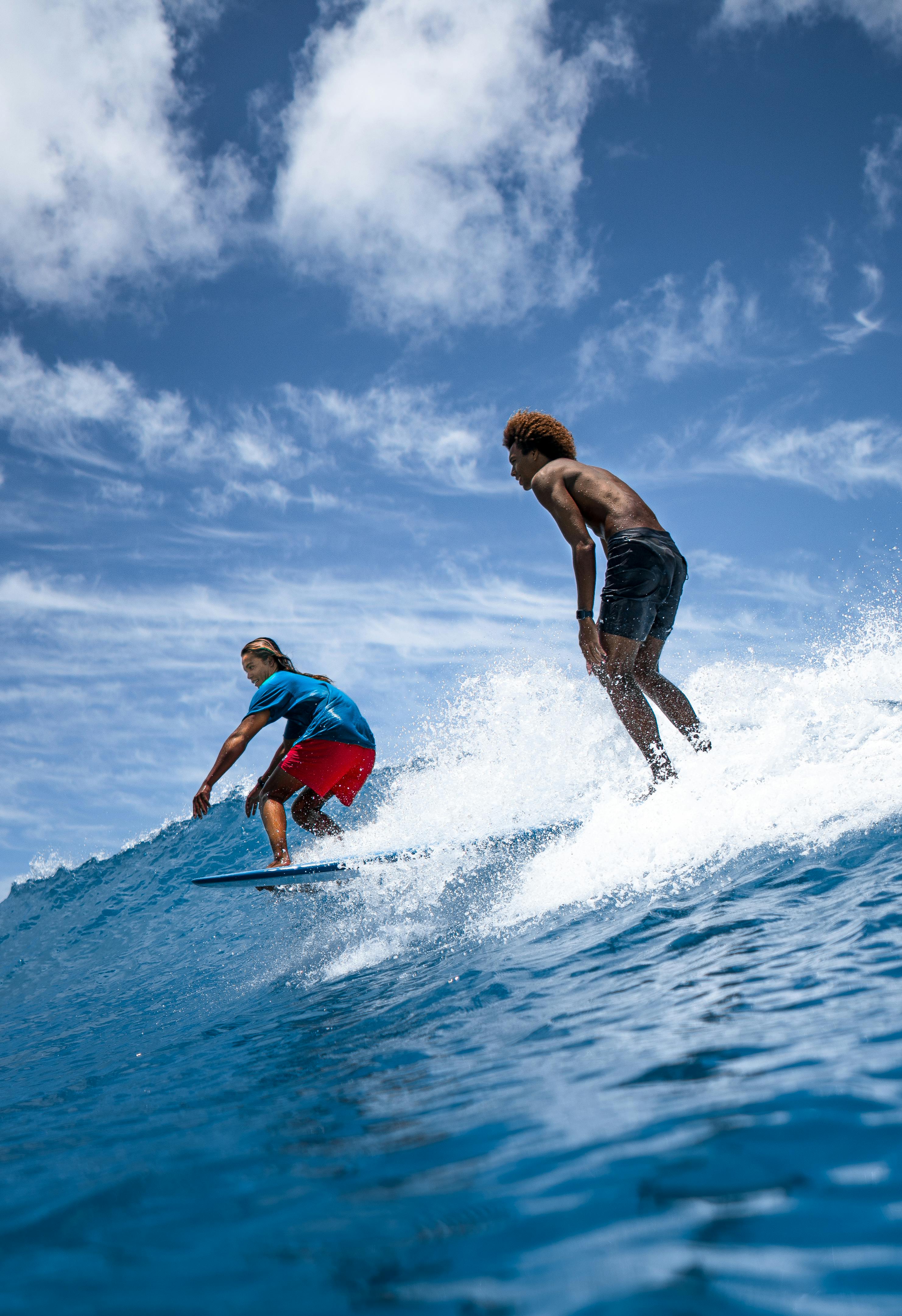 Multiethnic faceless friends surfing on boards in sea · Free Stock Photo