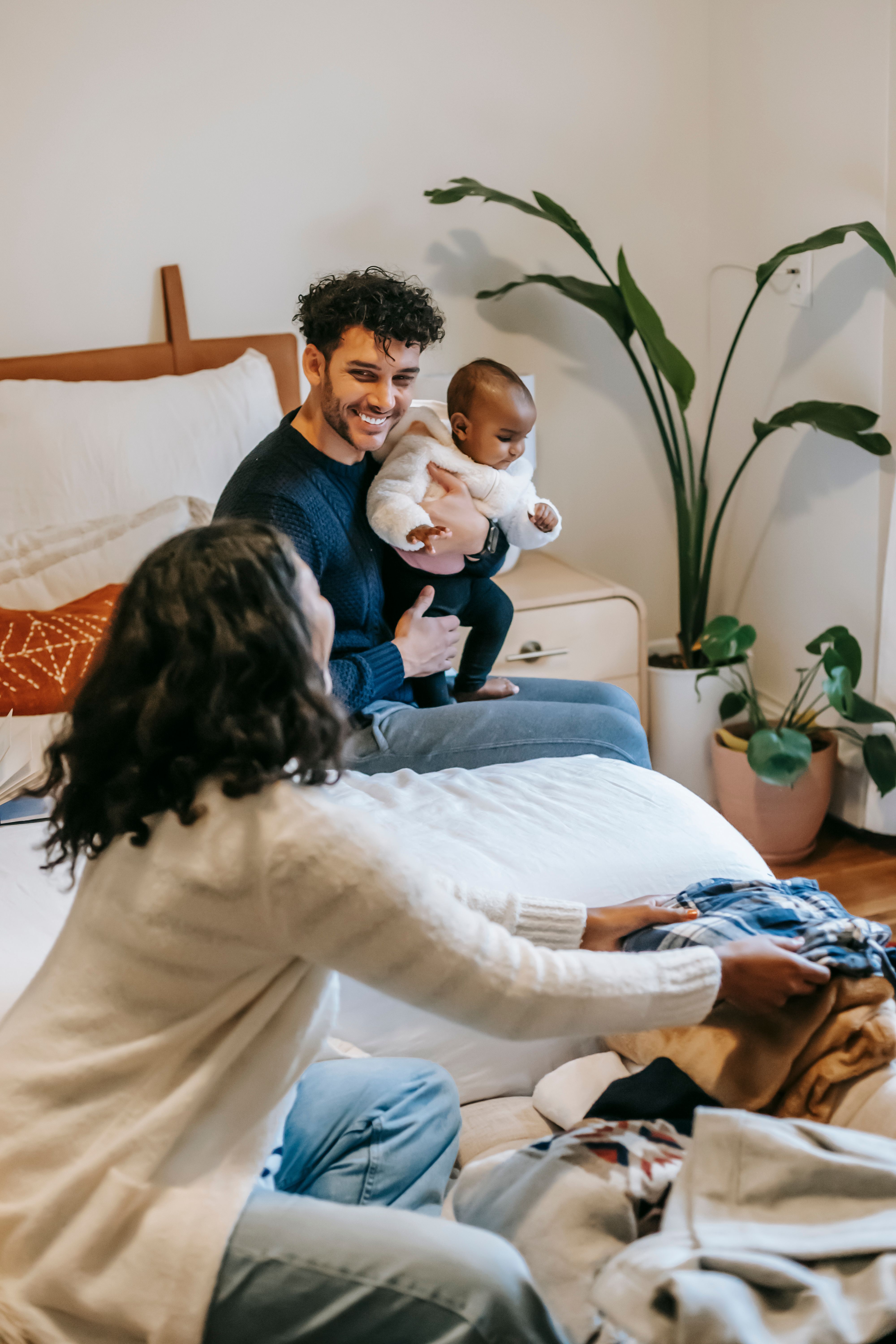 Multiethnic family with infant in bedroom · Free Stock Photo