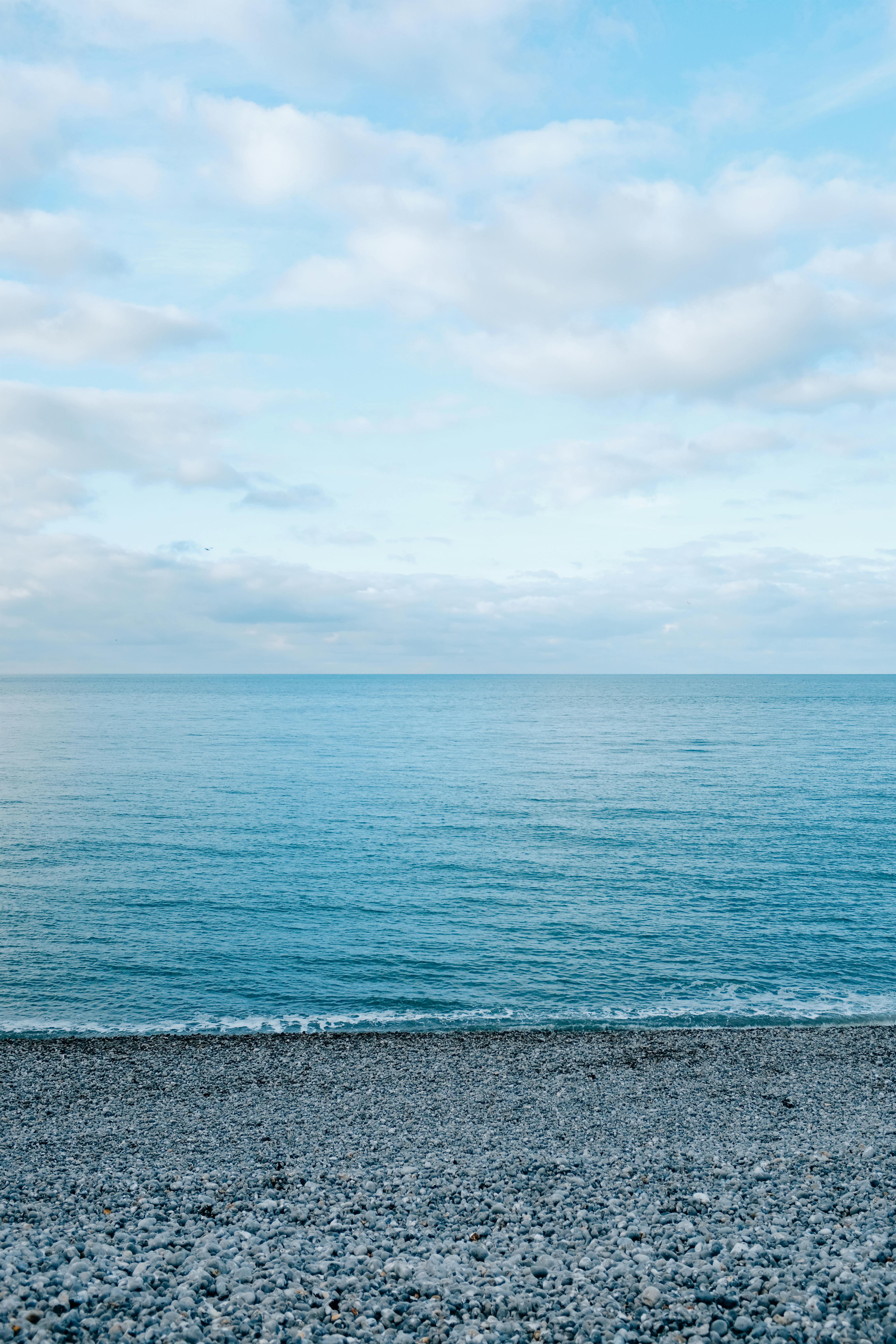 Calm rippling azure water of sea with coast with stones · Free Stock Photo