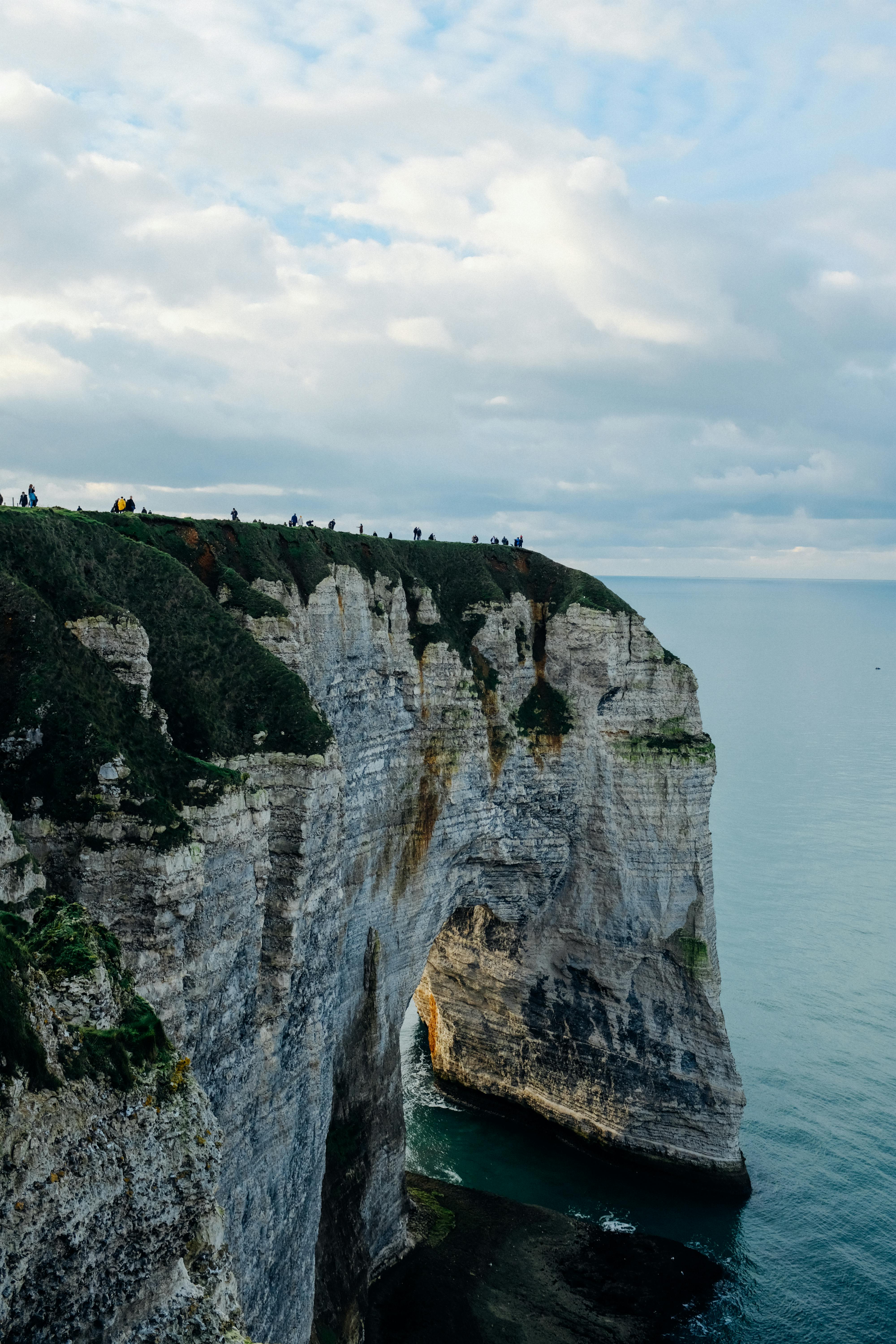 High rocky cliff with tourists near ocean · Free Stock Photo