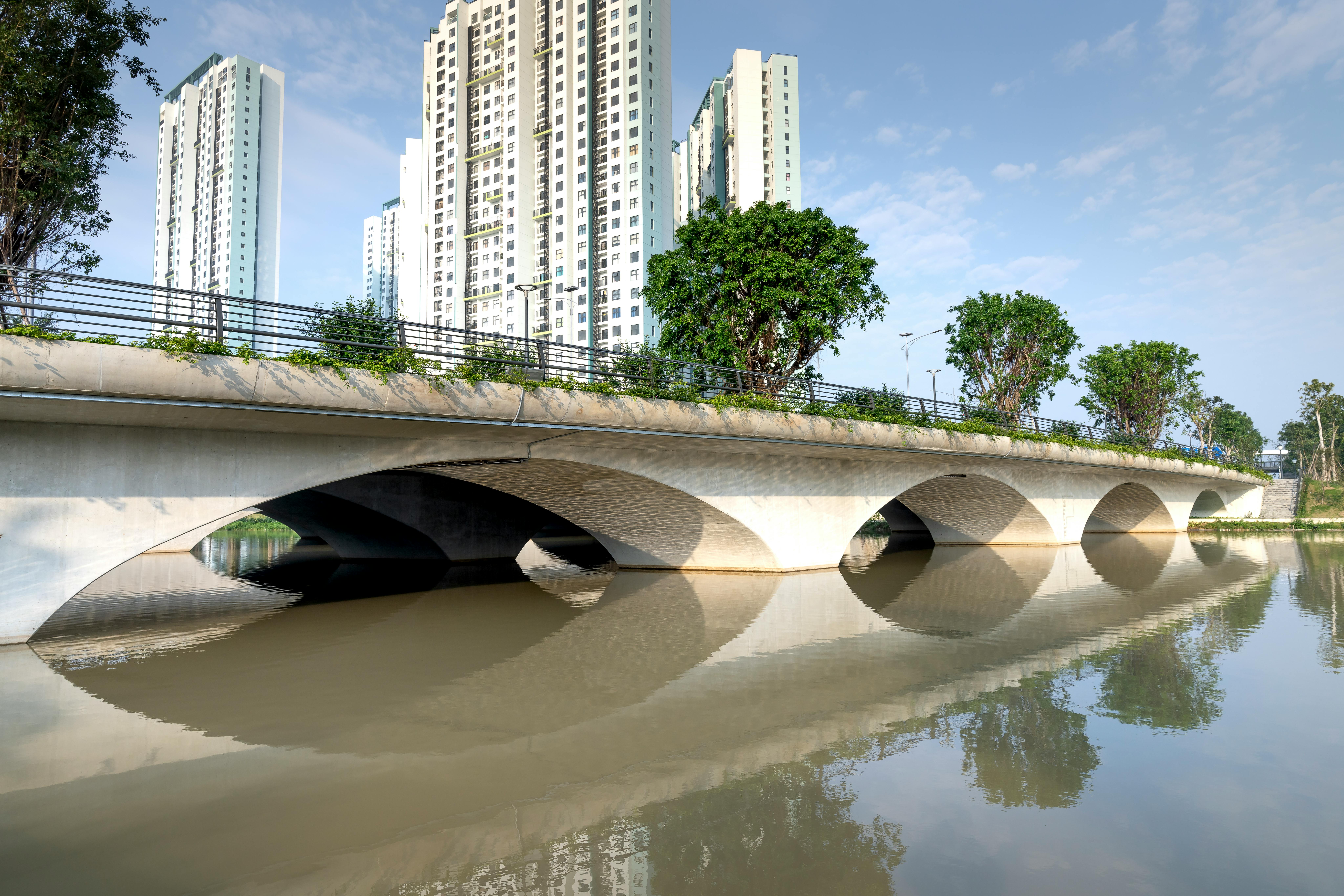 Arched bridge over river in modern city · Free Stock Photo