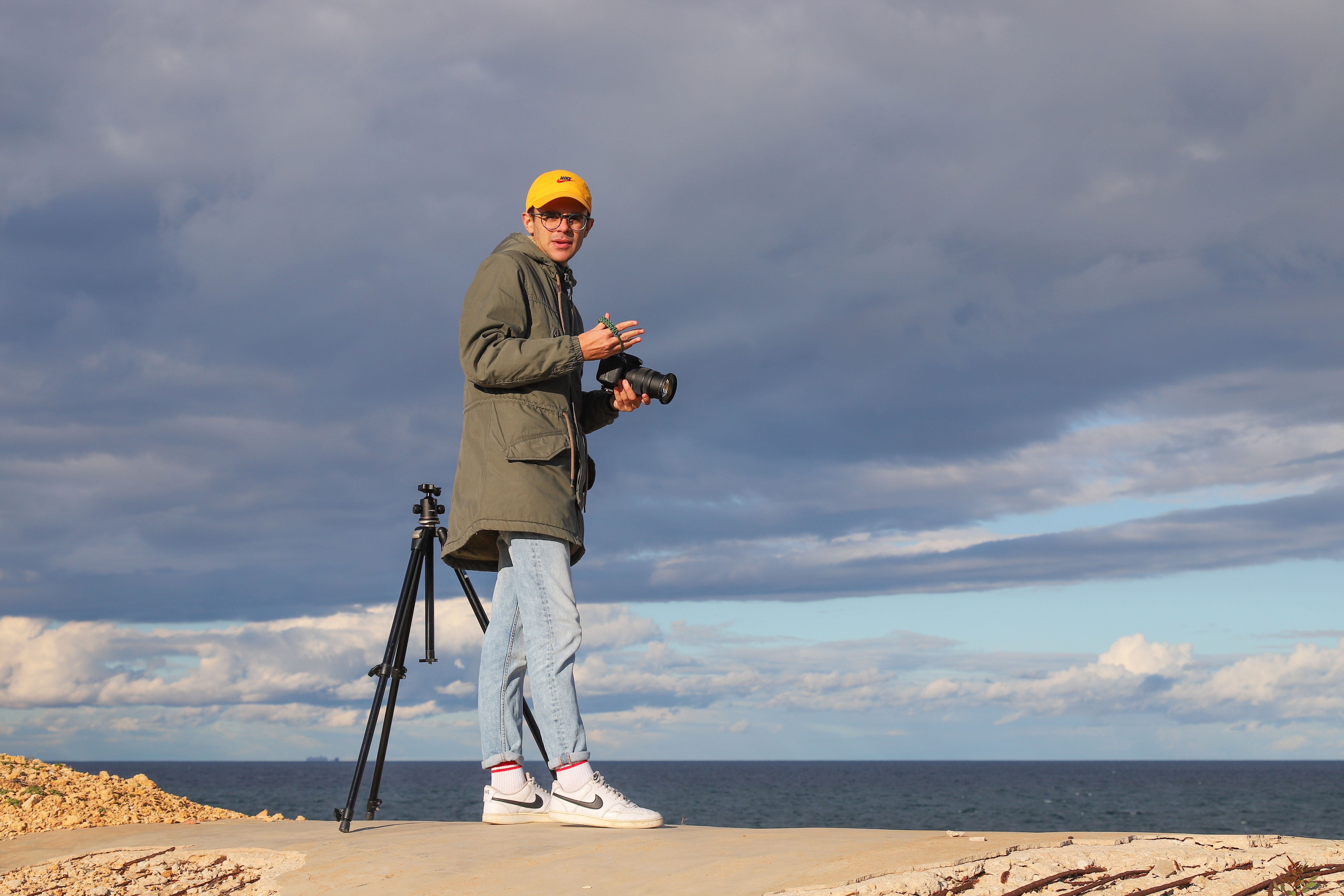 Man Standing On Pavement With Camera and Tripod · Free Stock Photo
