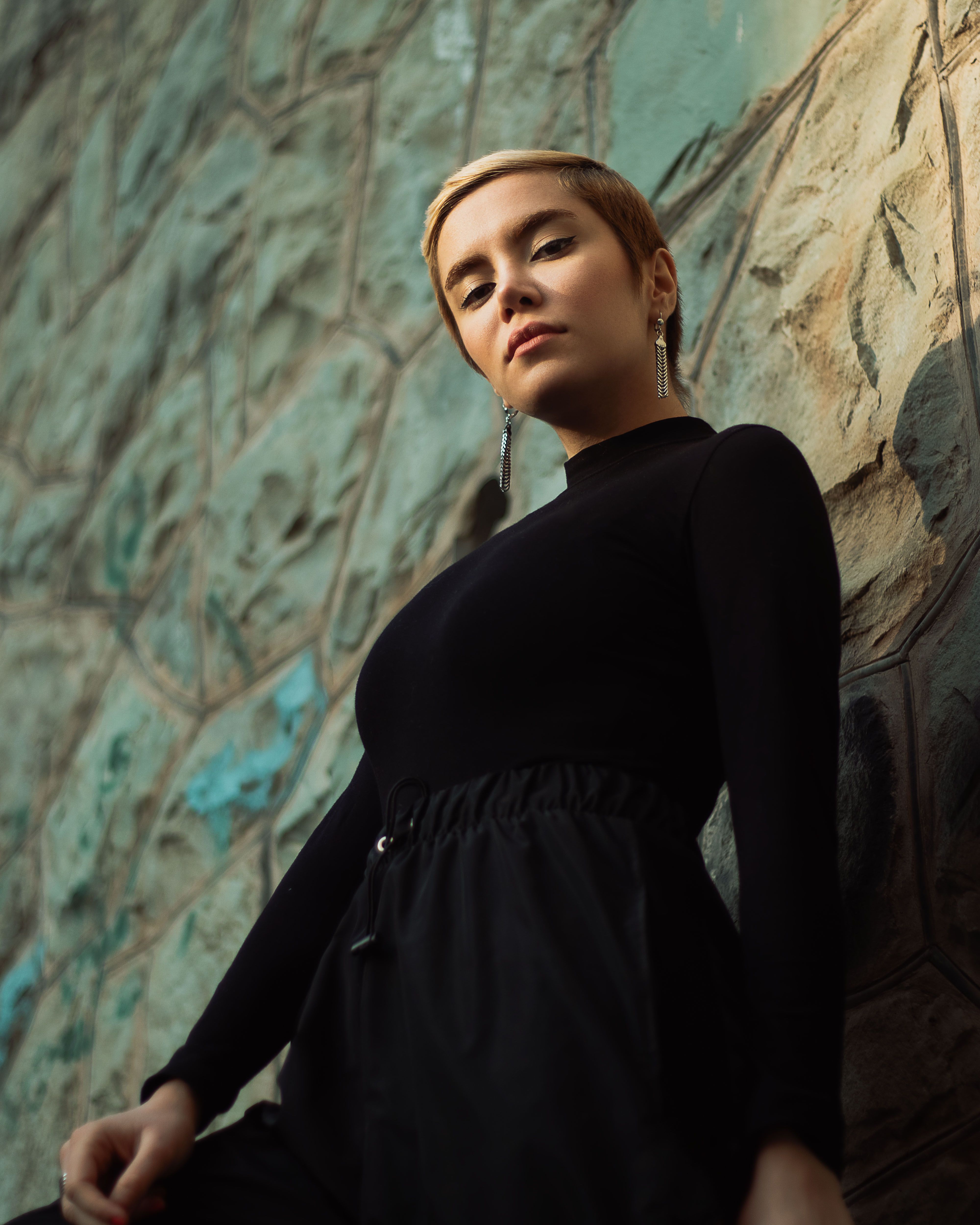 Serious woman standing near wall in light place · Free Stock Photo