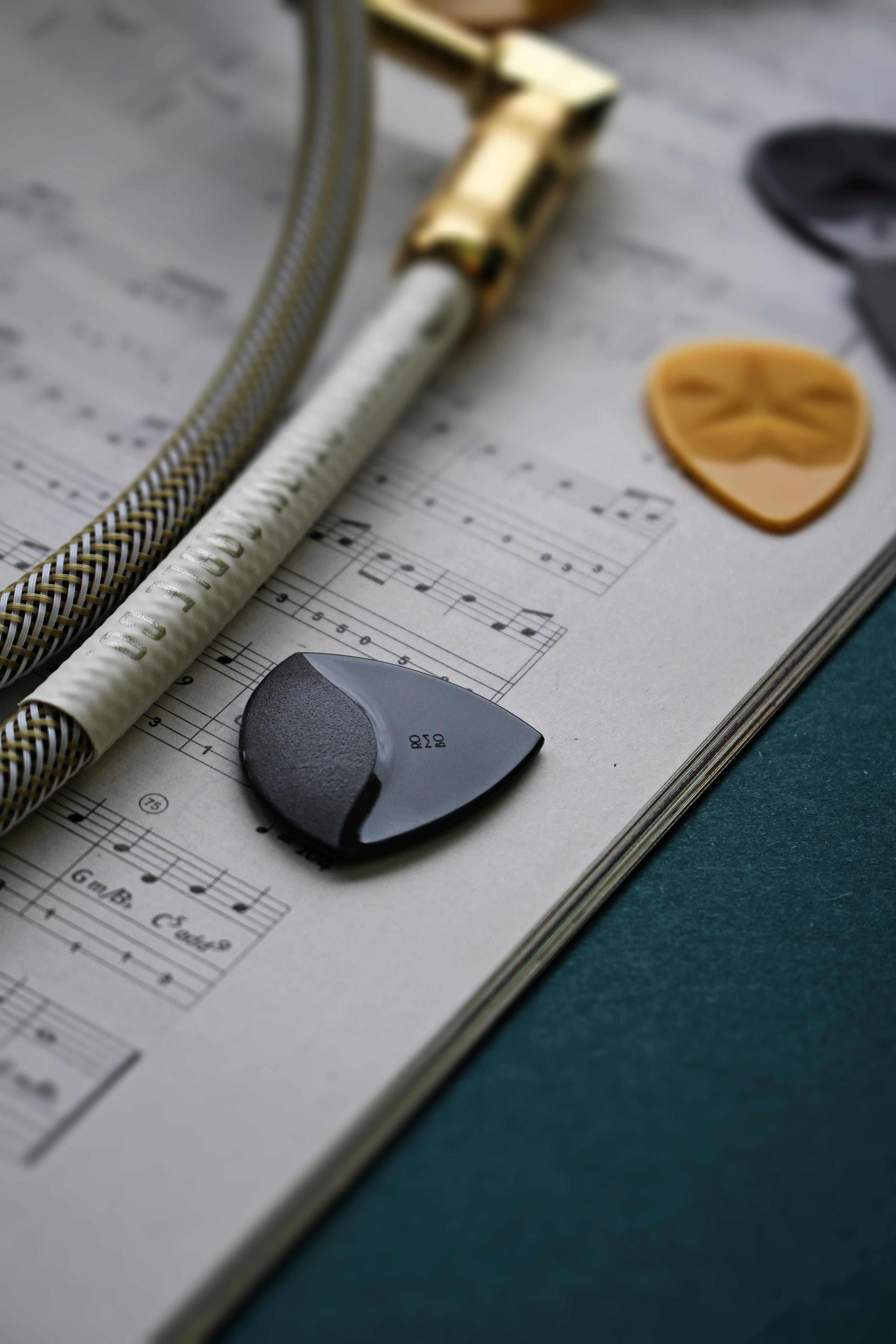 Guitar Picks on Music Sheet · Free Stock Photo