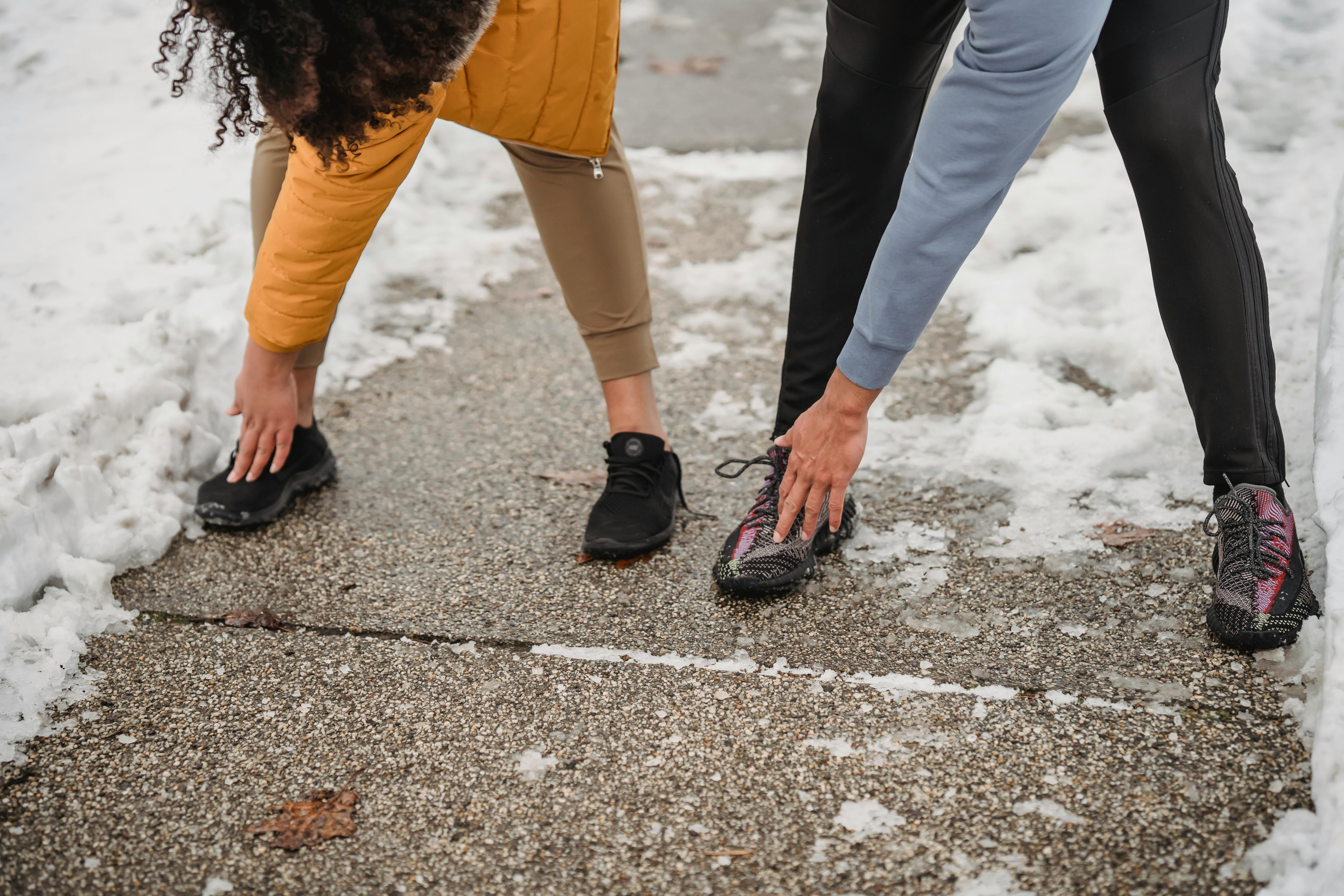 Crop faceless sportspeople doing windmill arm exercise on snowy ...
