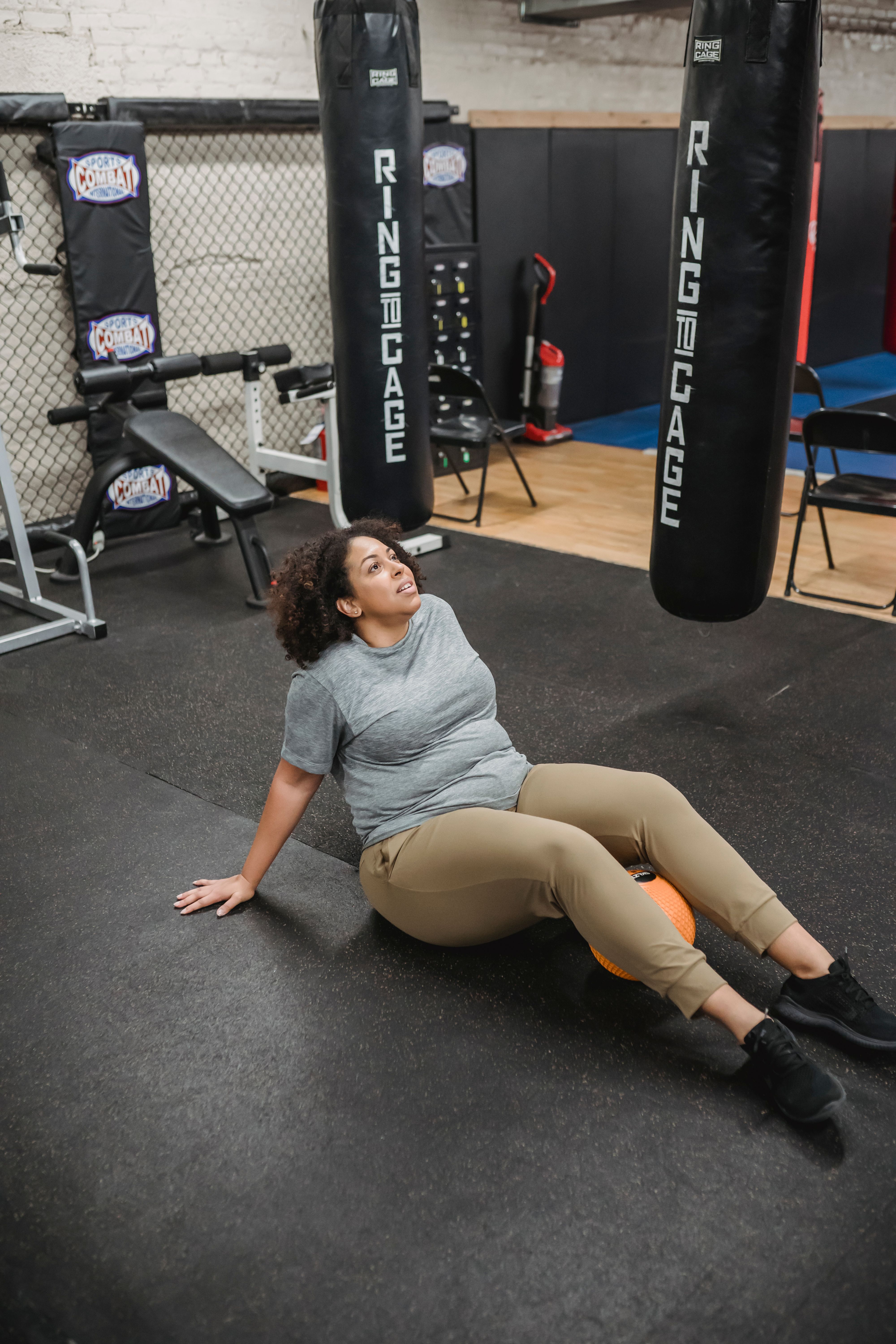 Overweight concentrated black woman exercising while rolling on ball ...