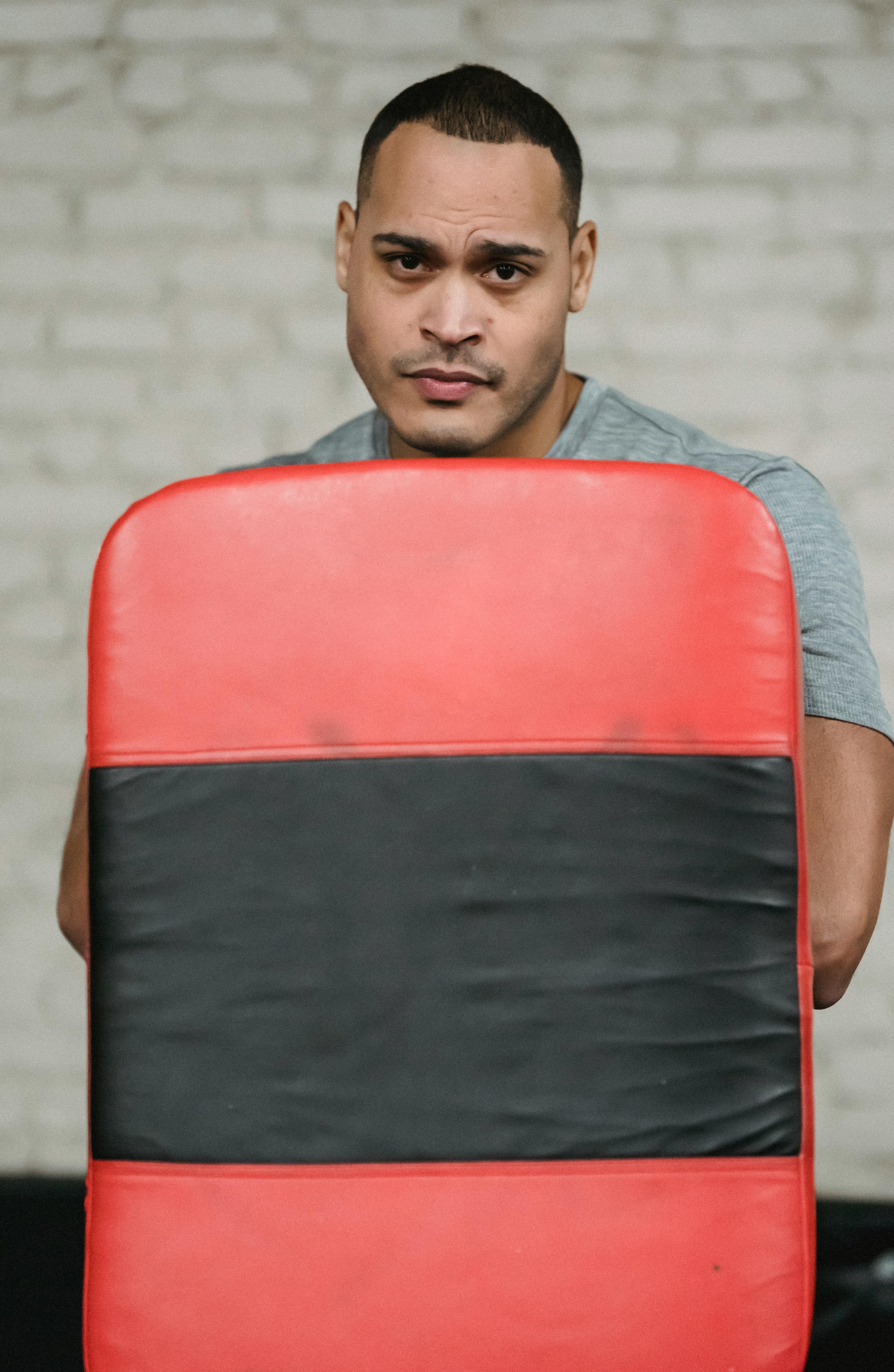 Serious young male boxer holding punching shield · Free Stock Photo