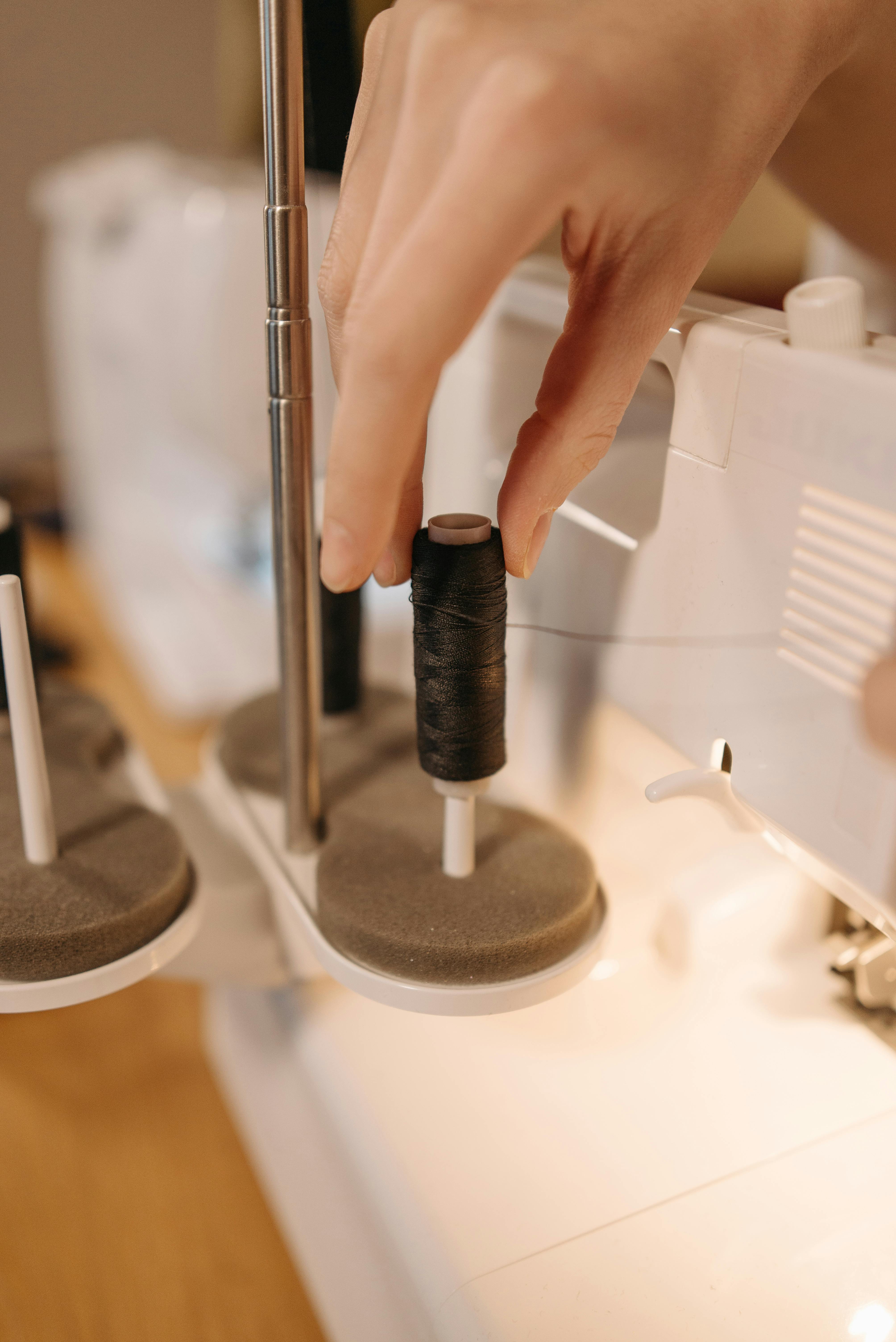 Hand Inserting Spool of Thread on Spool Pin · Free Stock Photo