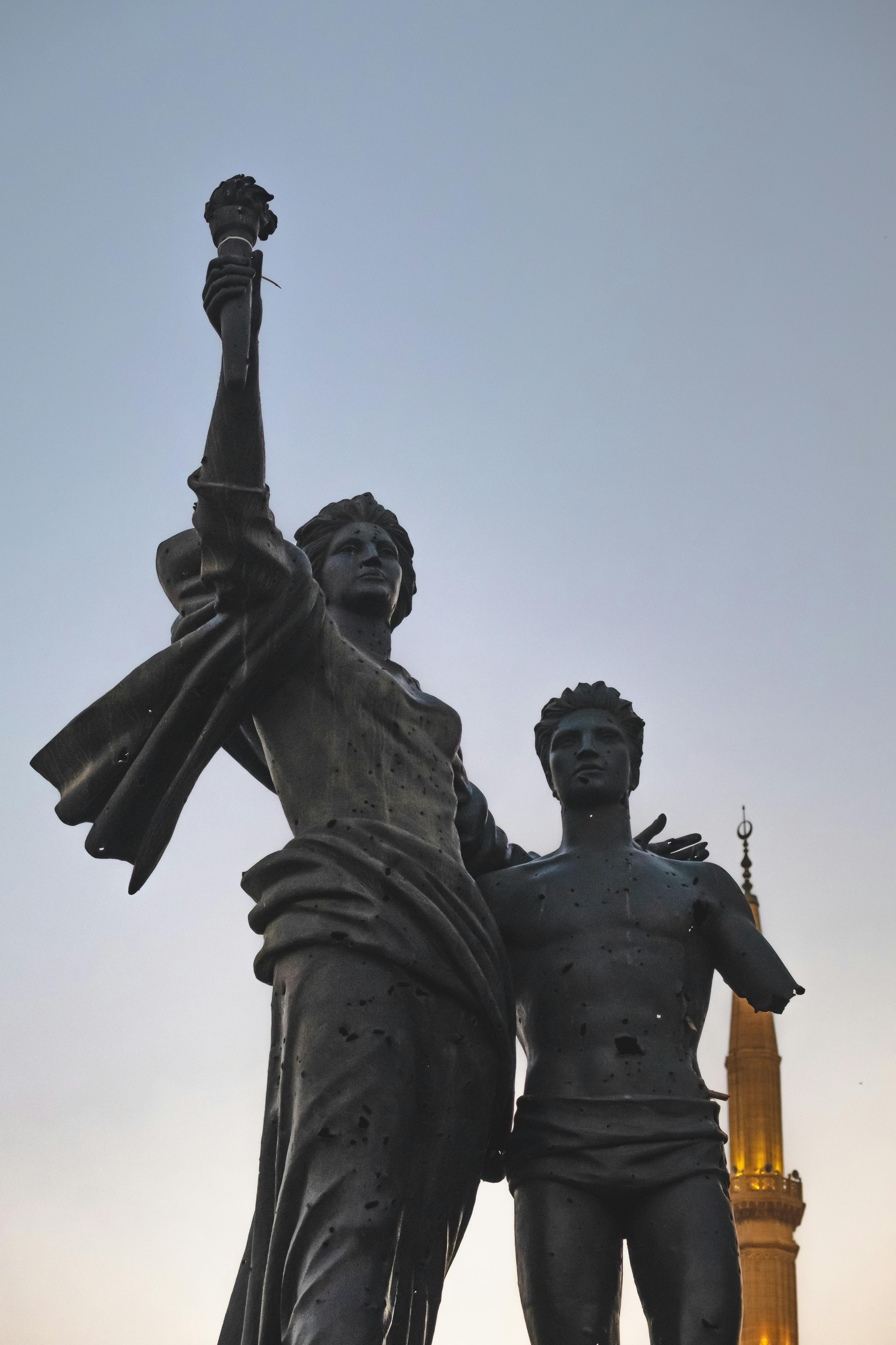 A Man Sitting on the Foot of a Giant Mouse Statue · Free Stock Photo