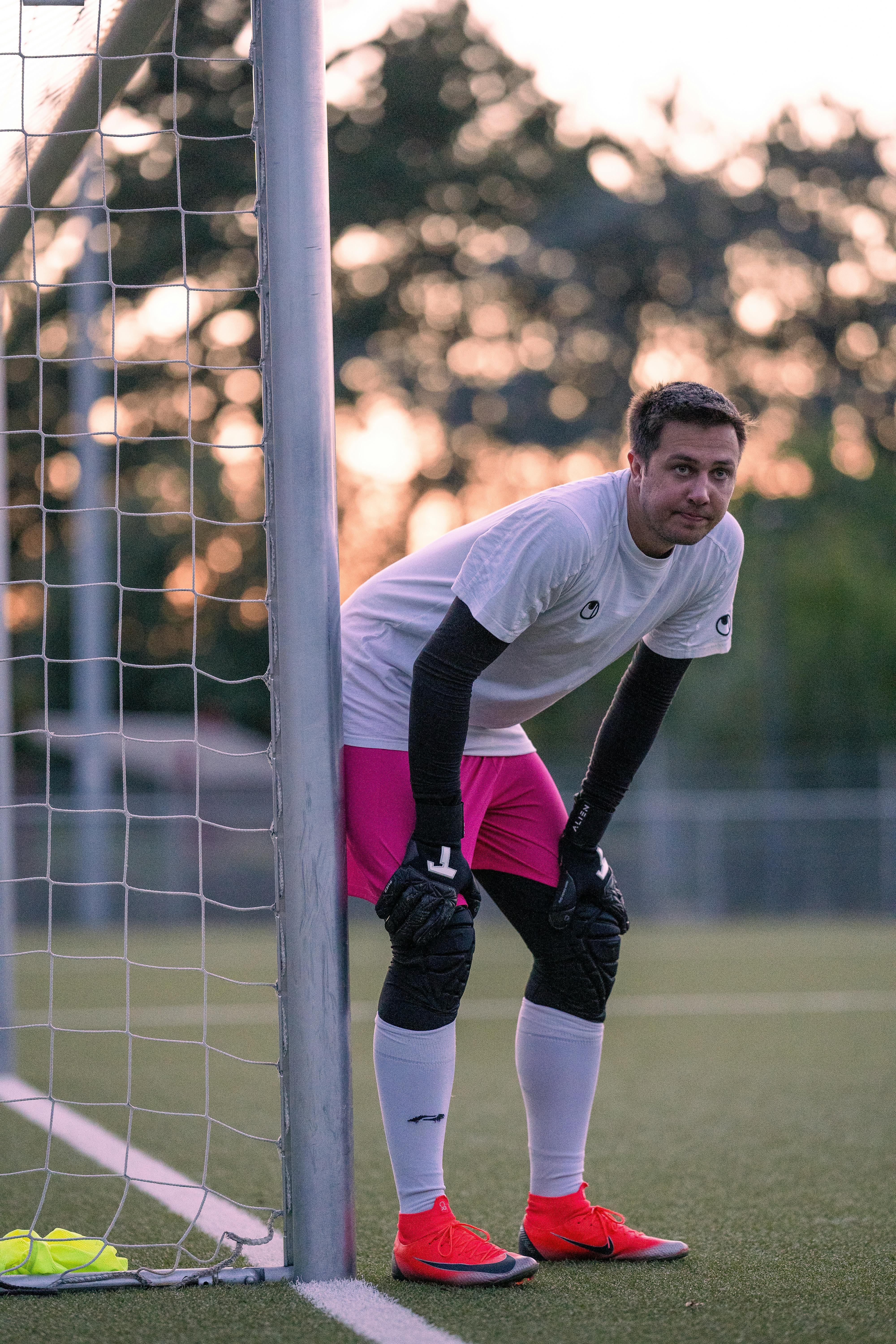 Goalkeeper standing near football goal in field · Free Stock Photo