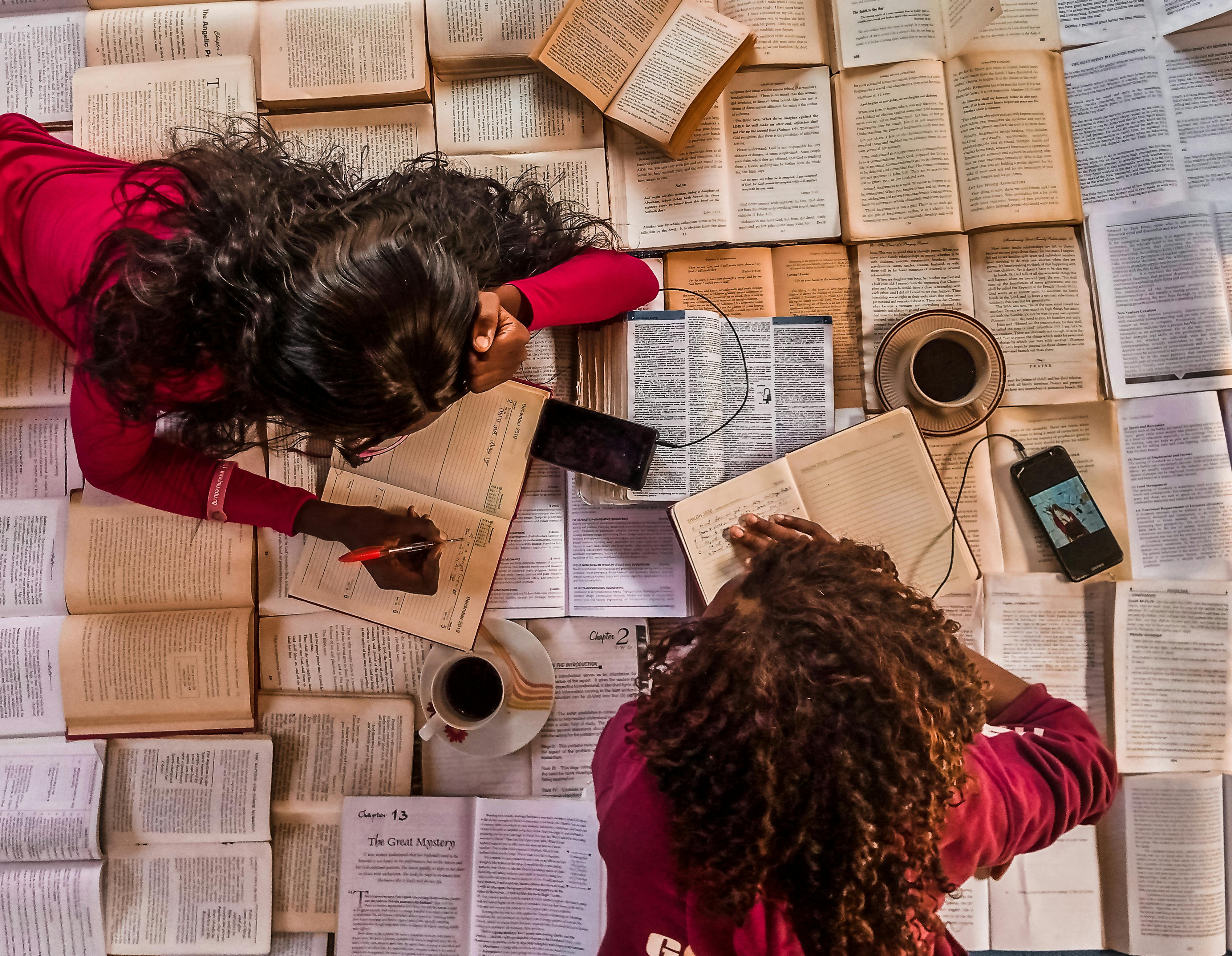 Overhead Shot of Two Women Writing while Reading Books · Free Stock Photo