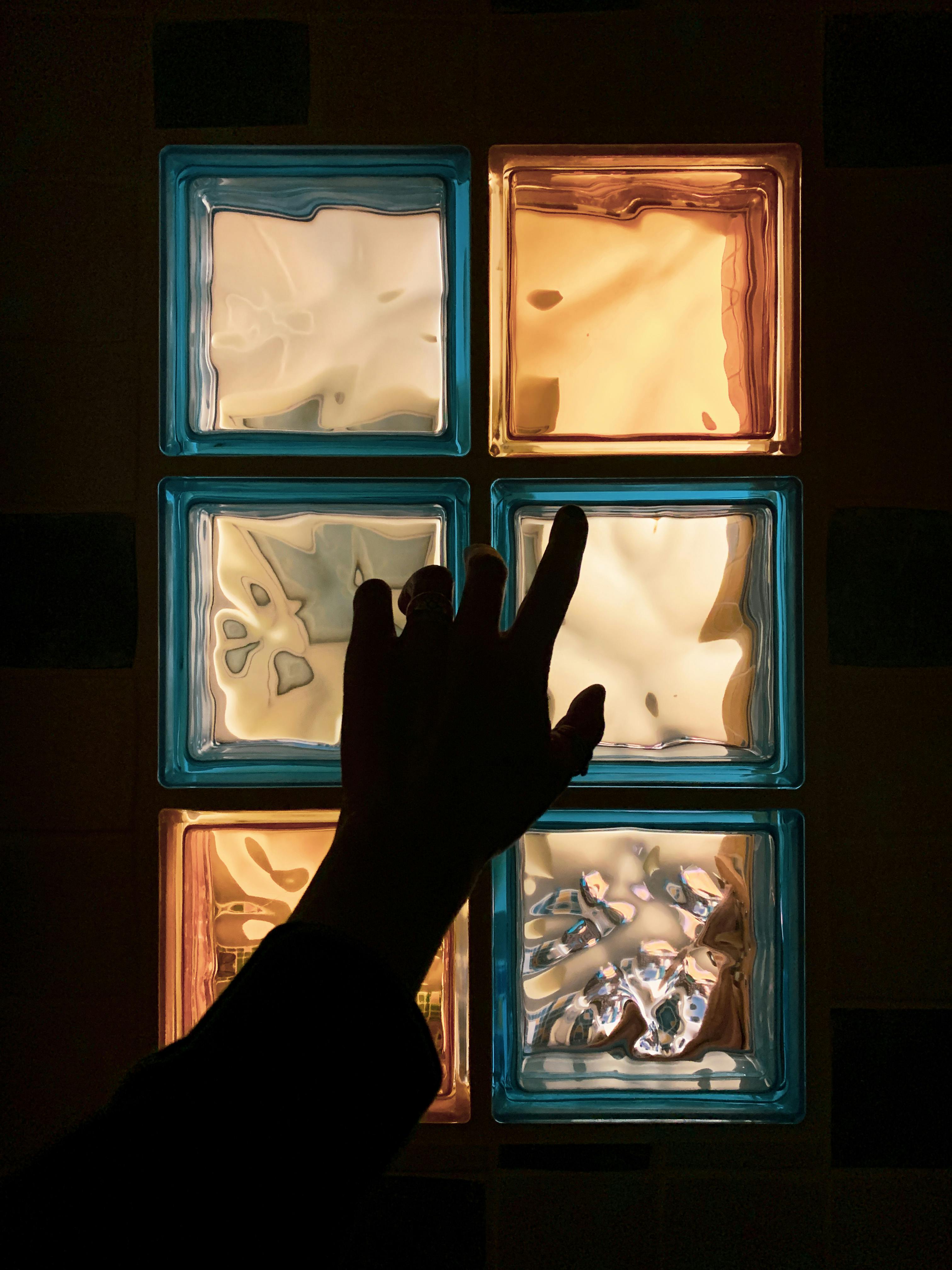 Person touching glass block window with hand · Free Stock Photo