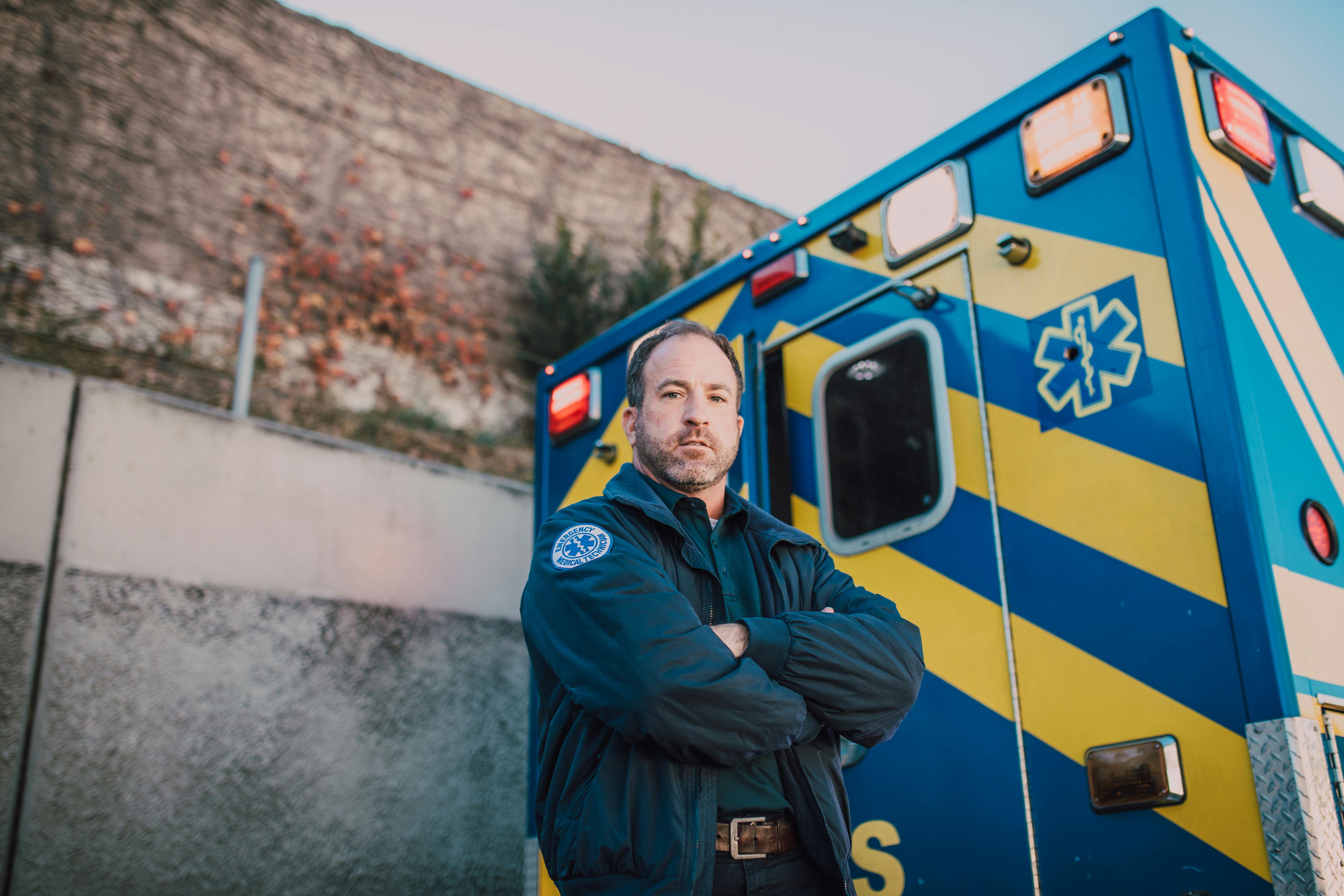 EMT Standing Behind an Ambulance · Free Stock Photo