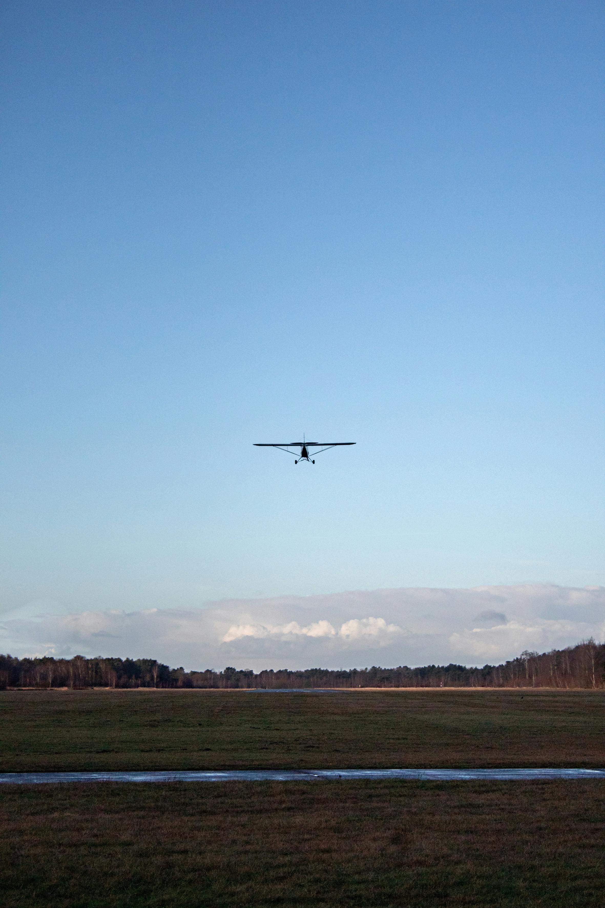 An Airplane Flying Over an Open Field · Free Stock Photo
