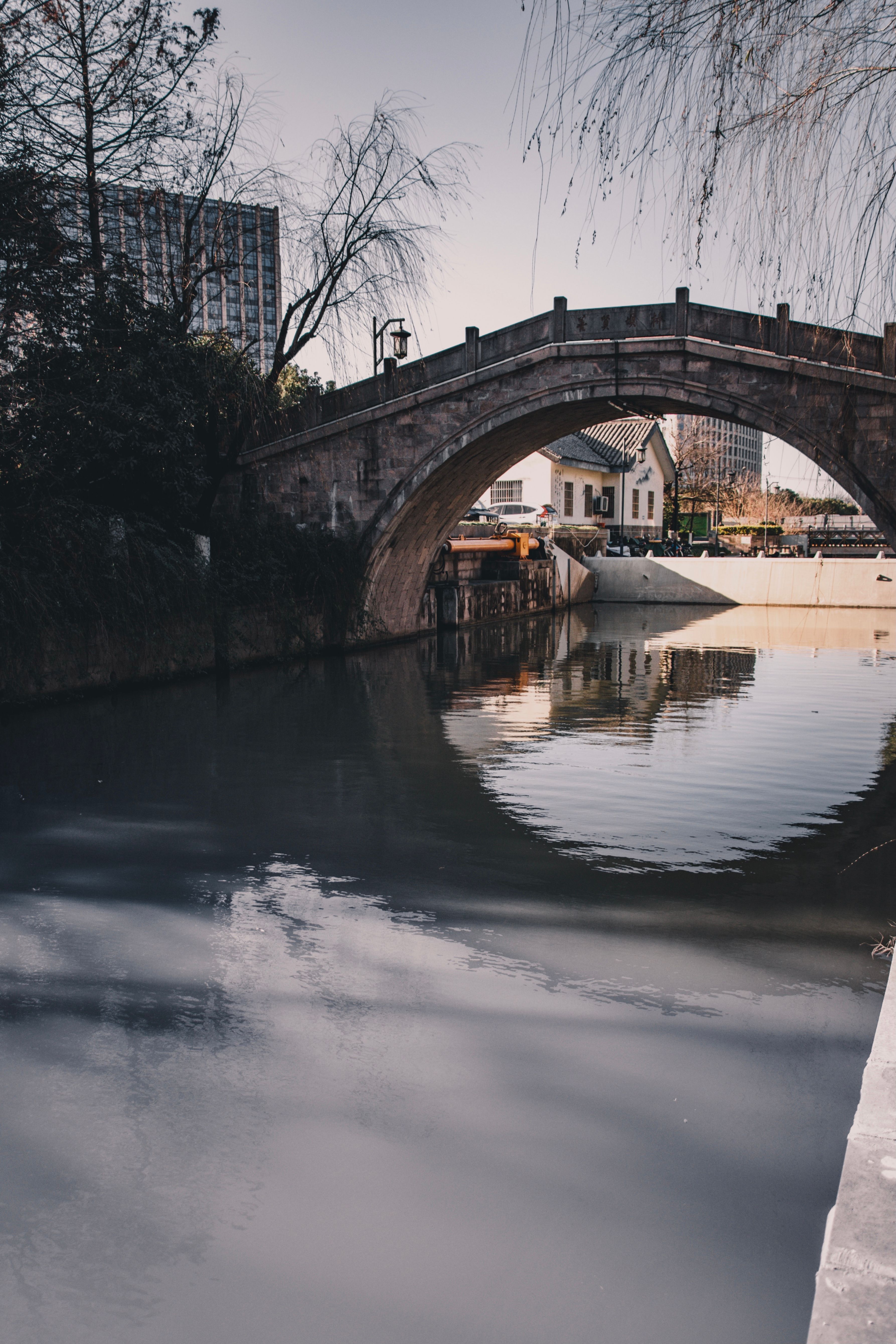 Old arched bridge over calm canal · Free Stock Photo