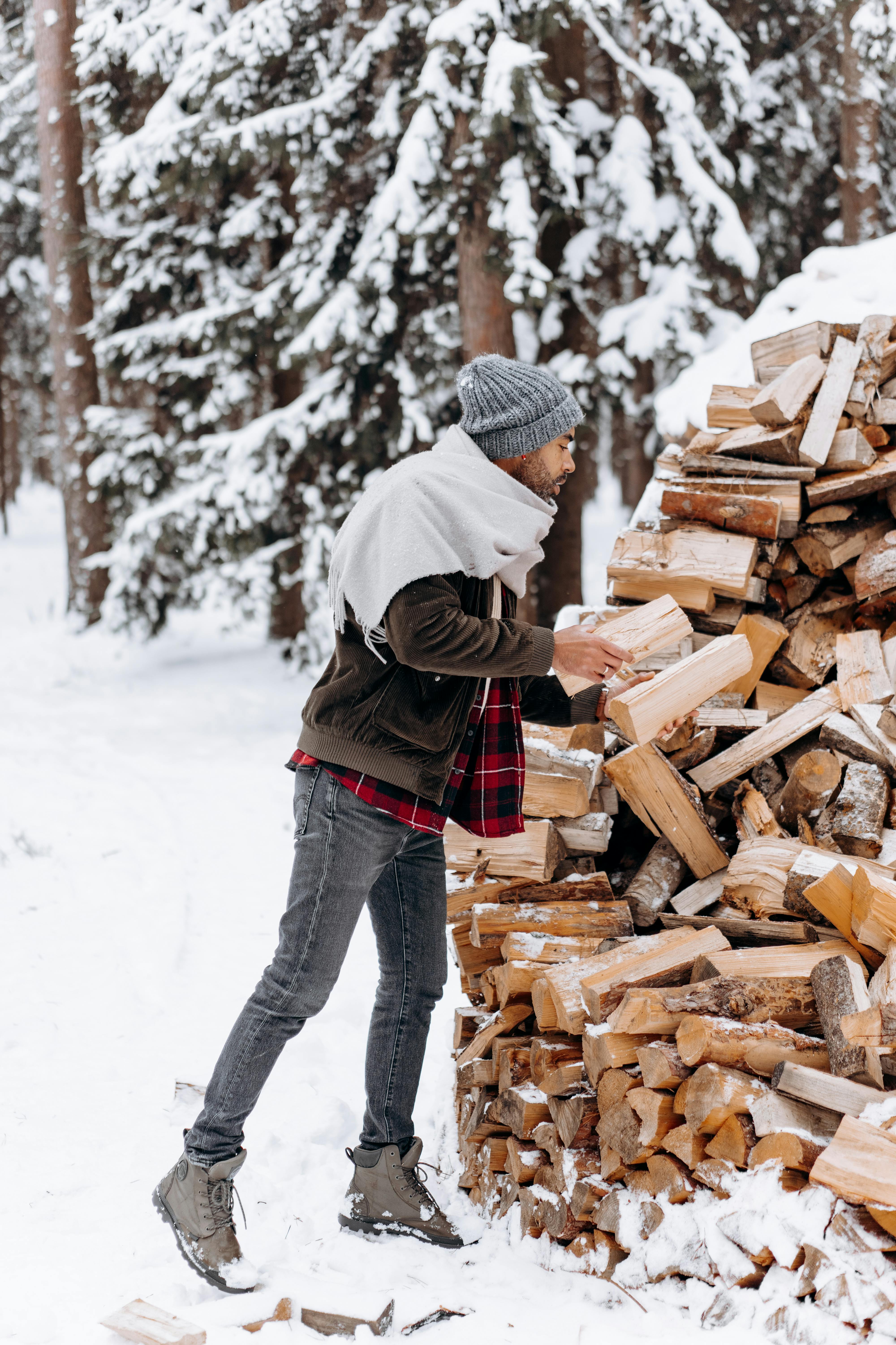 A Man Stacking Firewood in a Winter Forest · Free Stock Photo