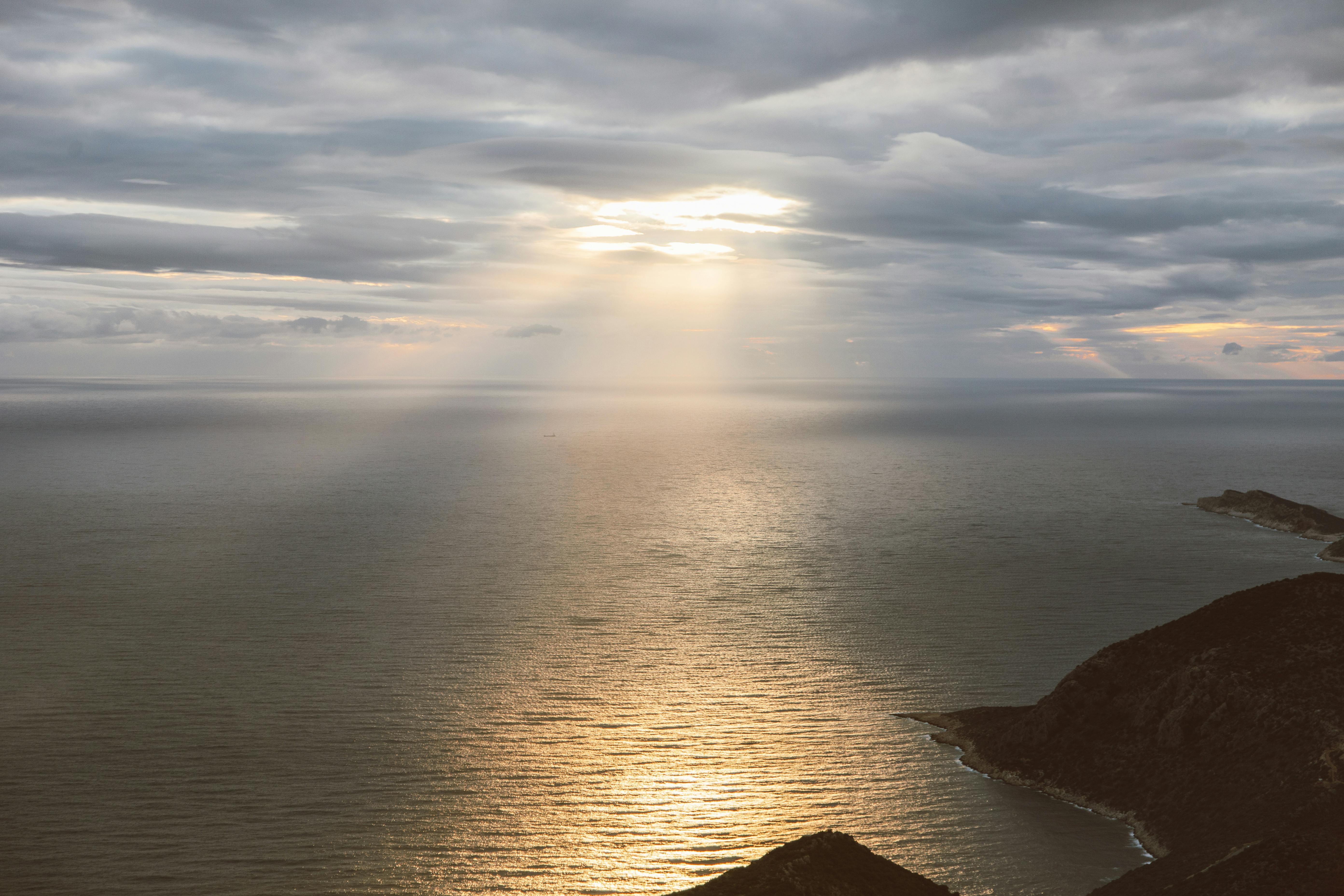A Cloudy Sky with Sunbeam Over the Ocean · Free Stock Photo
