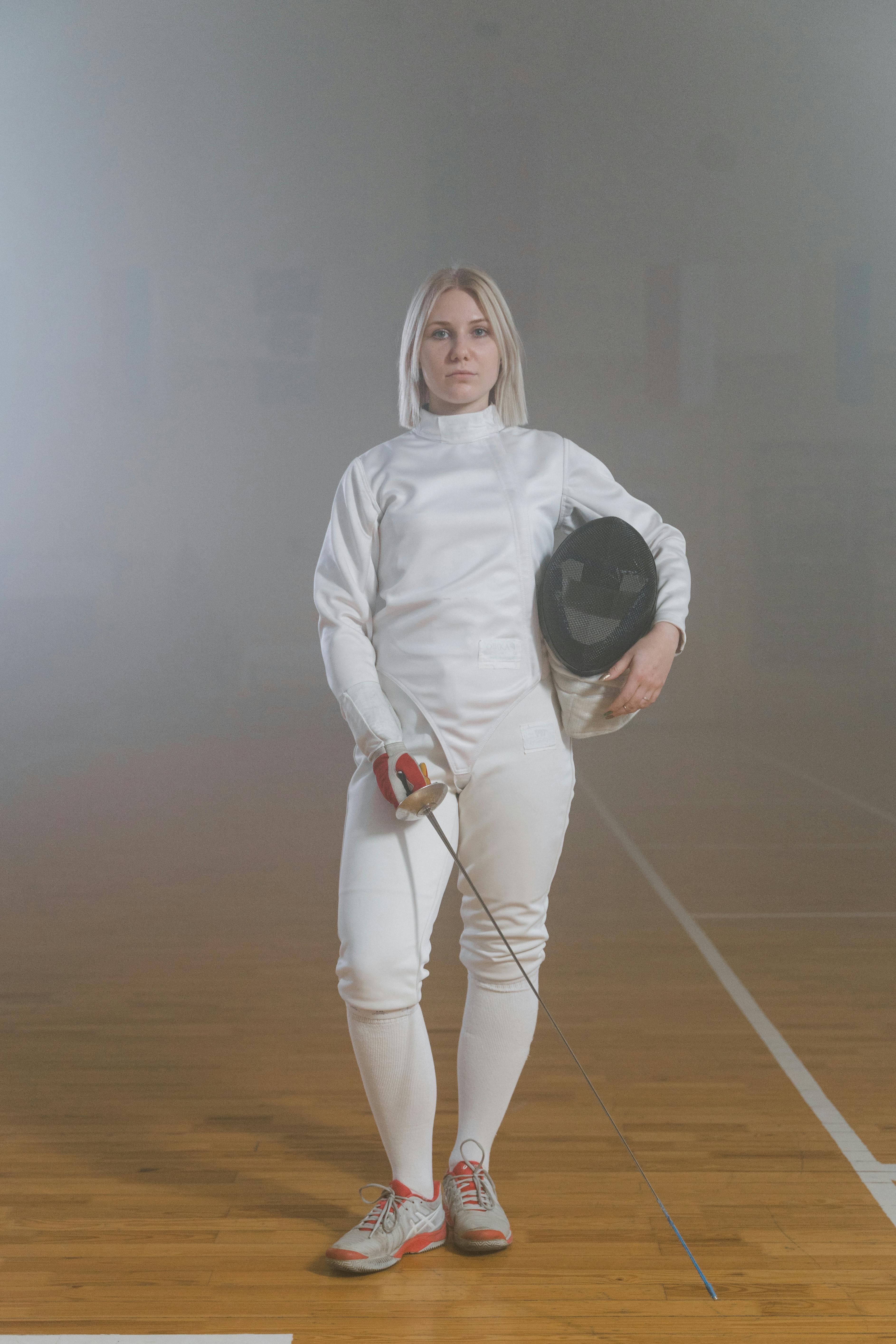 A Woman in fencing Uniform Holding a Fencing Mask and a Sword · Free ...