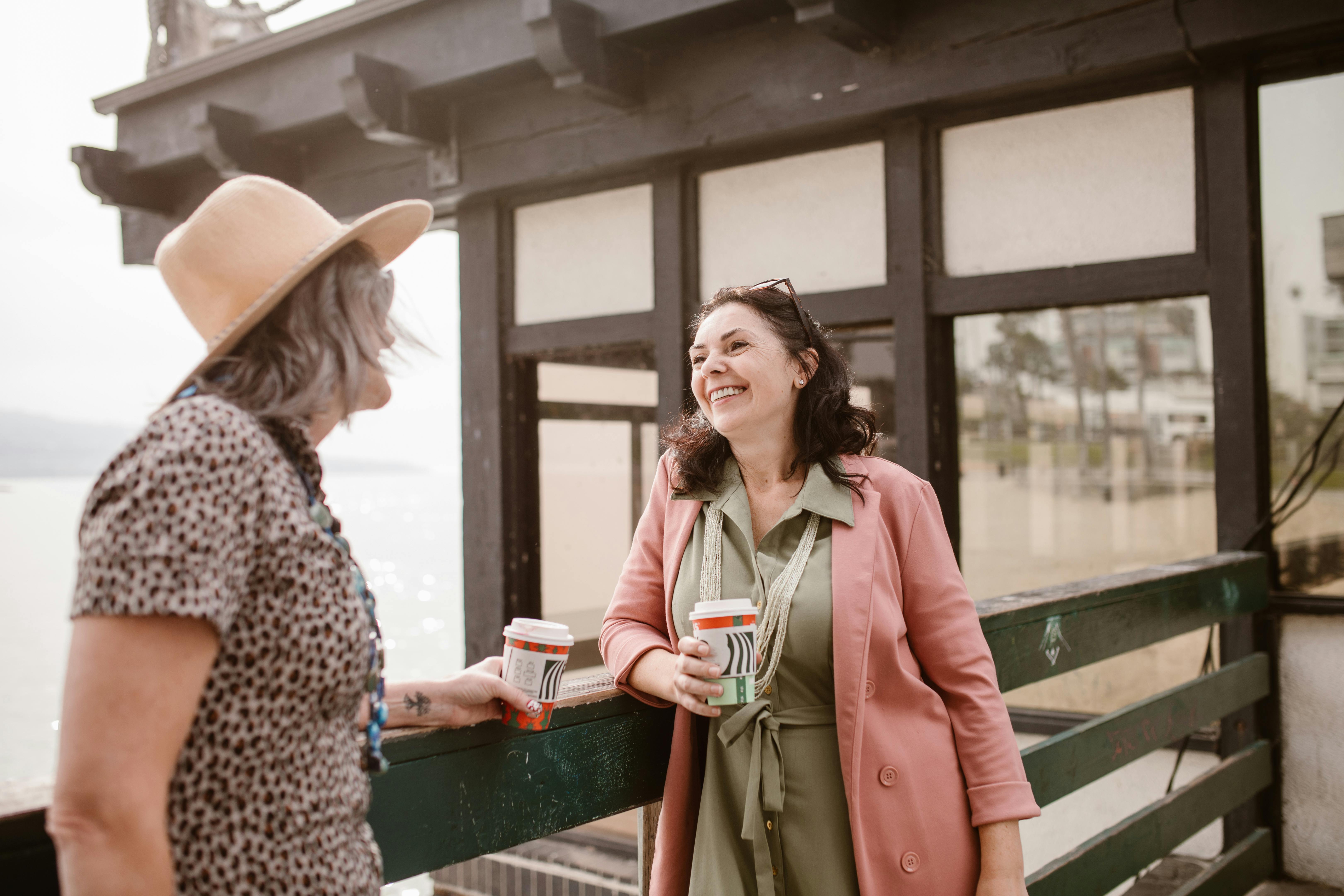 Women Having a Good Conversation While Standing Near the Wooden Railing ...