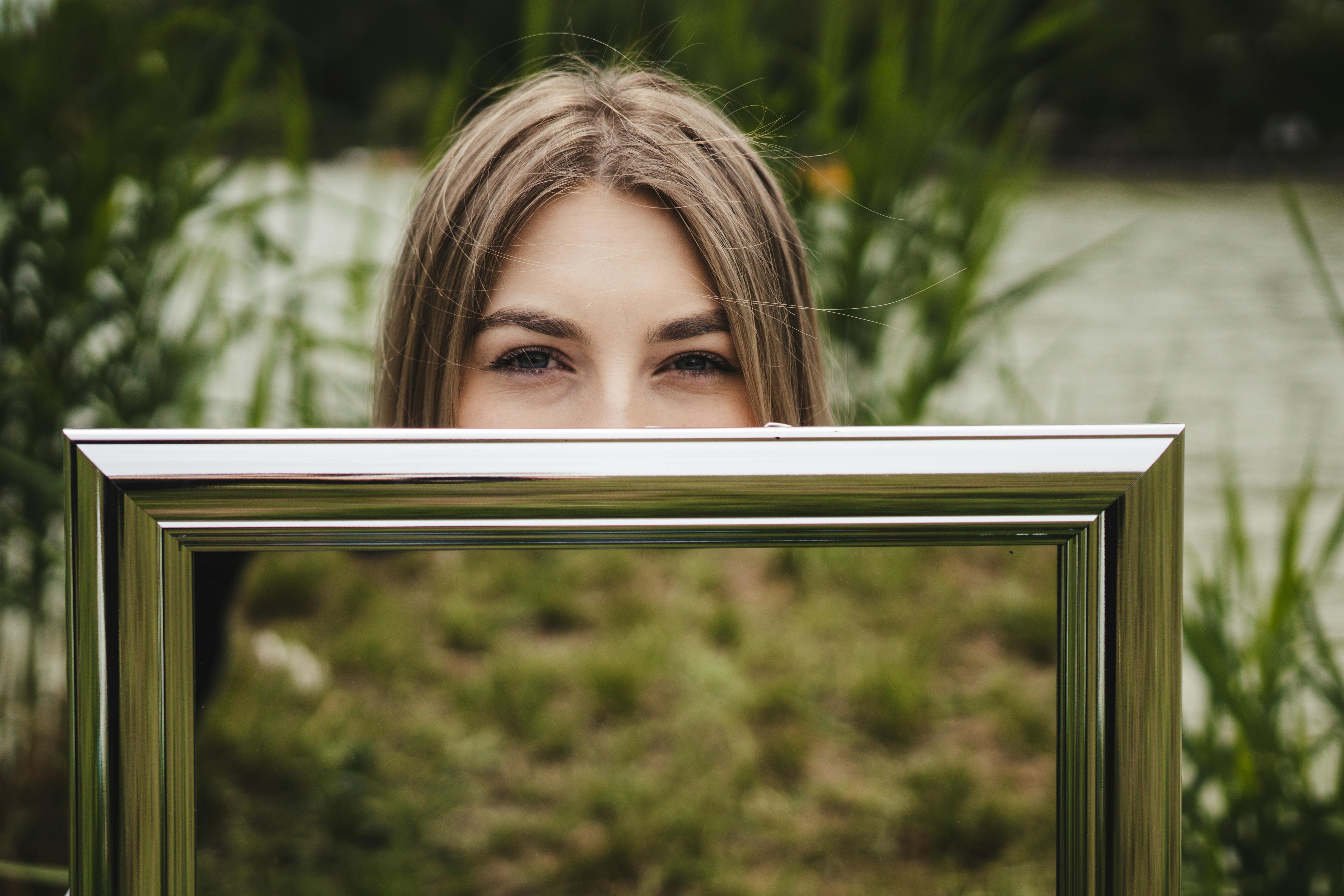 Woman Holding a Mirror Outdoors · Free Stock Photo