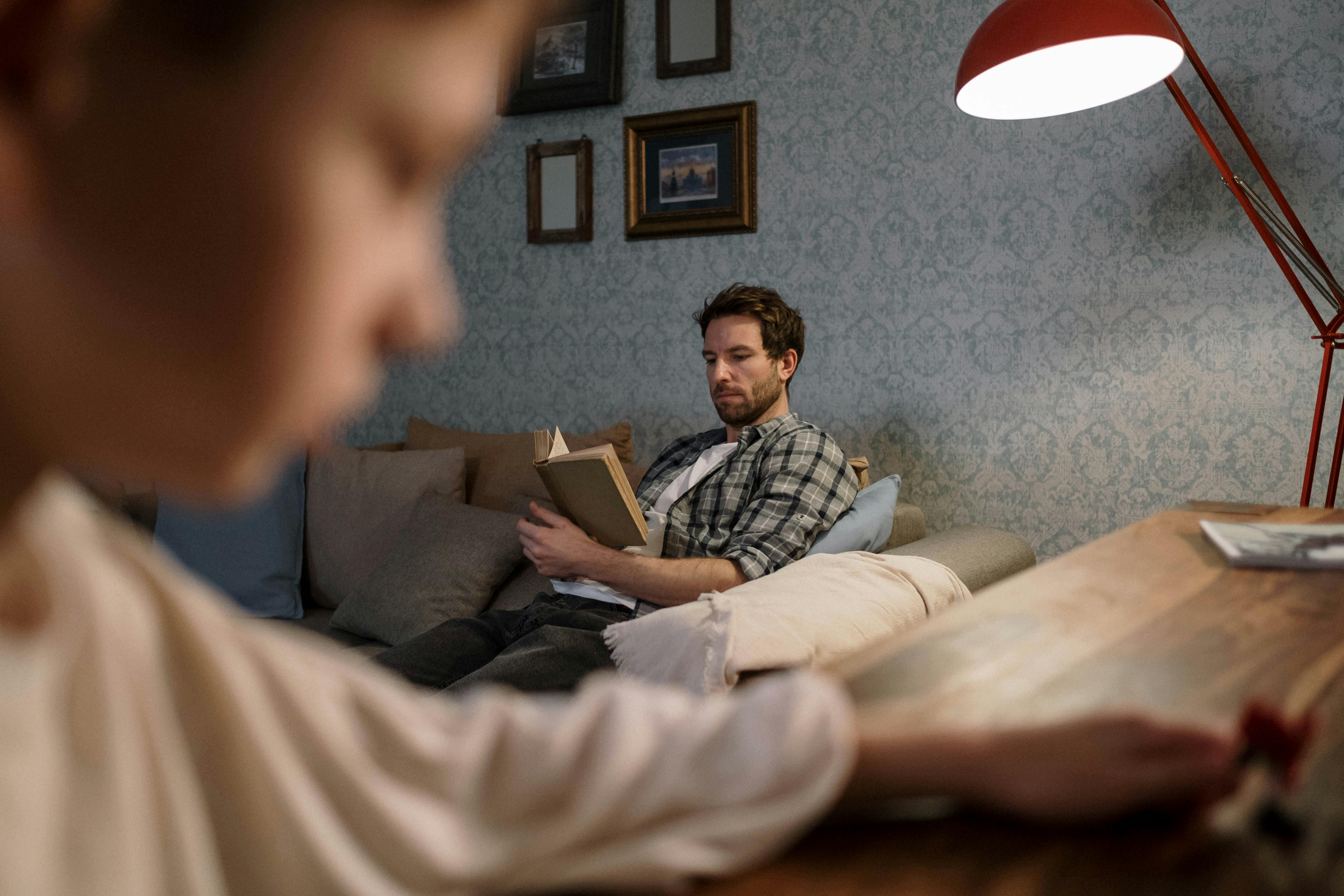 A Man Reading Book while Sitting on a Bed · Free Stock Photo