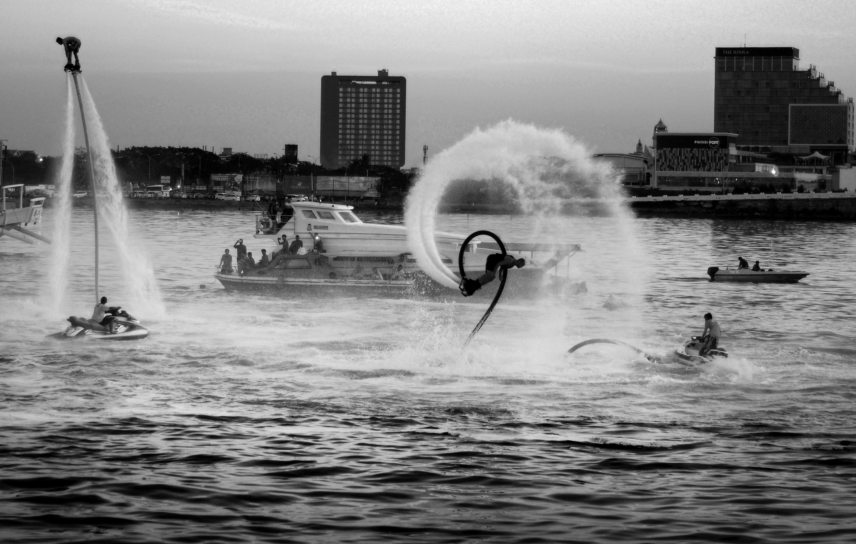 Grayscale Photo of People Doing Flyboarding · Free Stock Photo