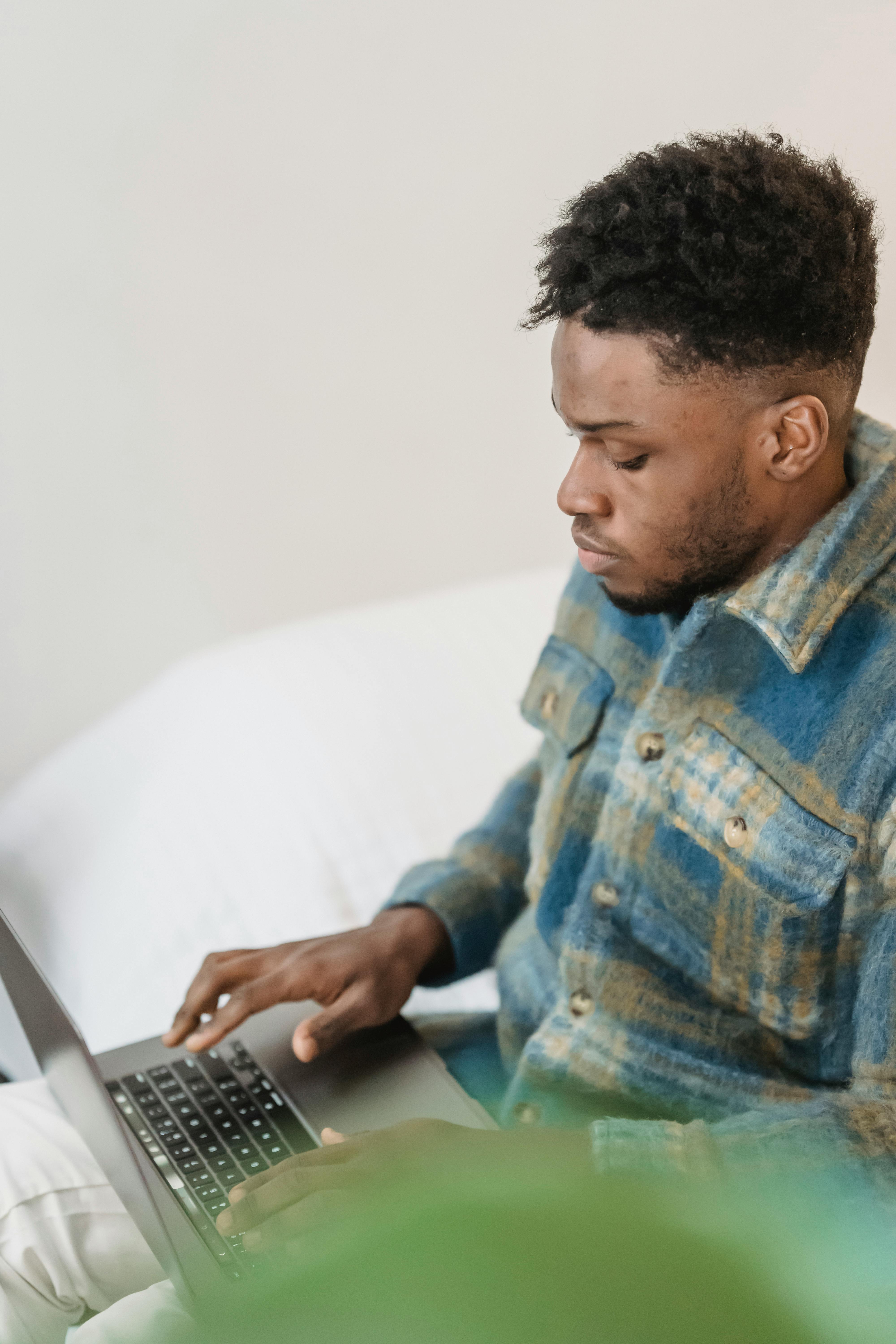Serious black guy typing on laptop · Free Stock Photo
