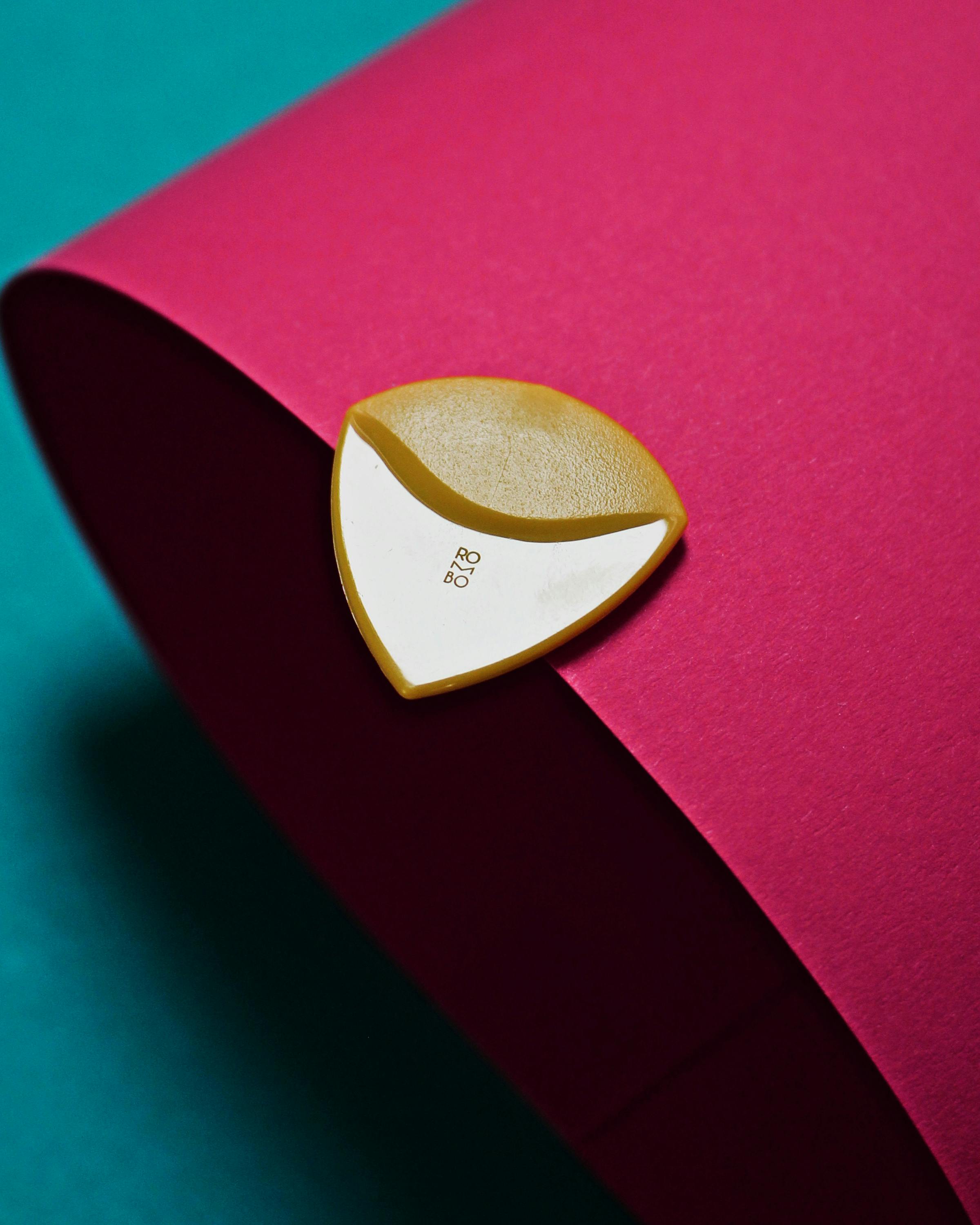 Gold Guitar Pick on Red Paper · Free Stock Photo